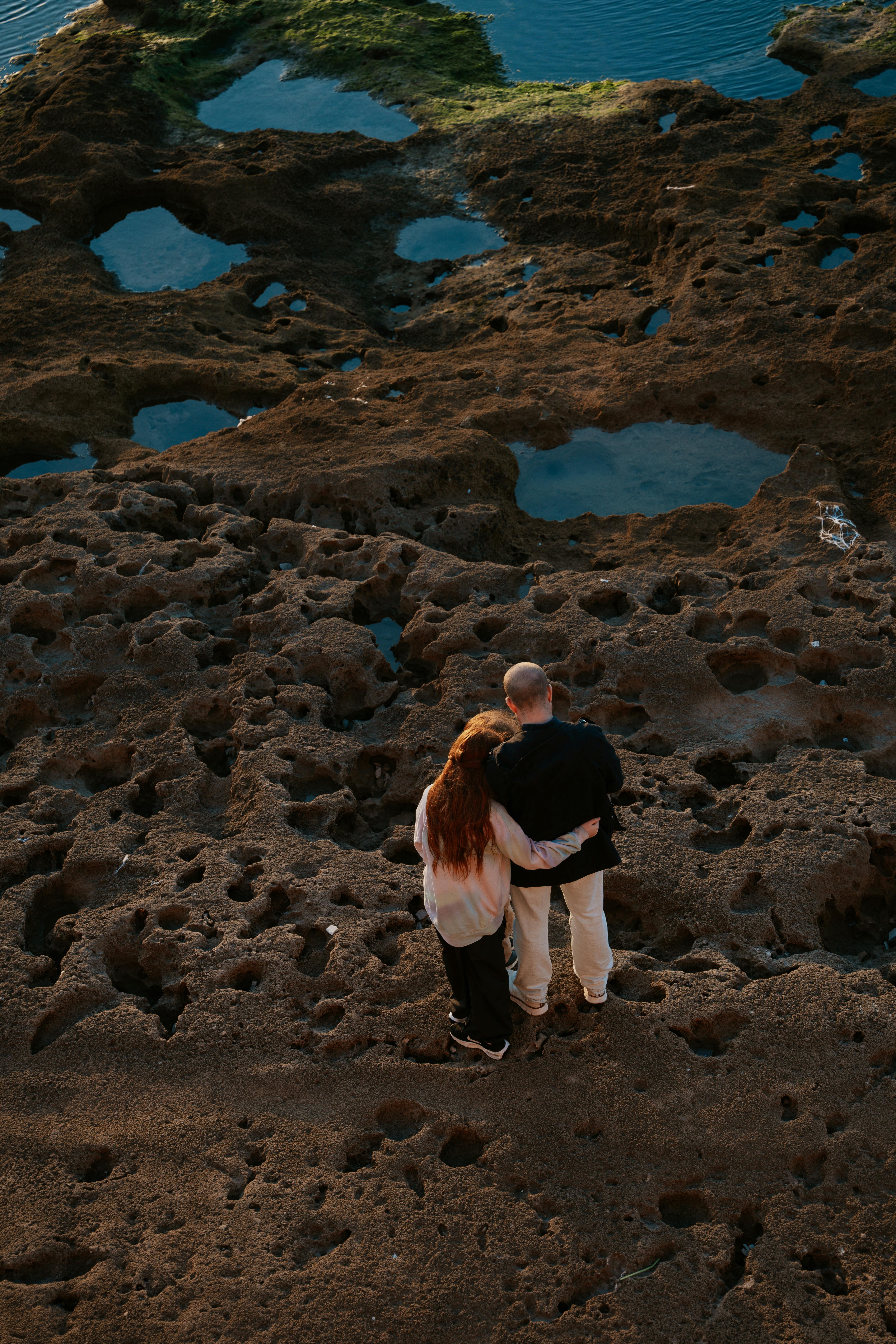 Romantic Couple Embracing on Rugged Coastline · Free Stock Photo