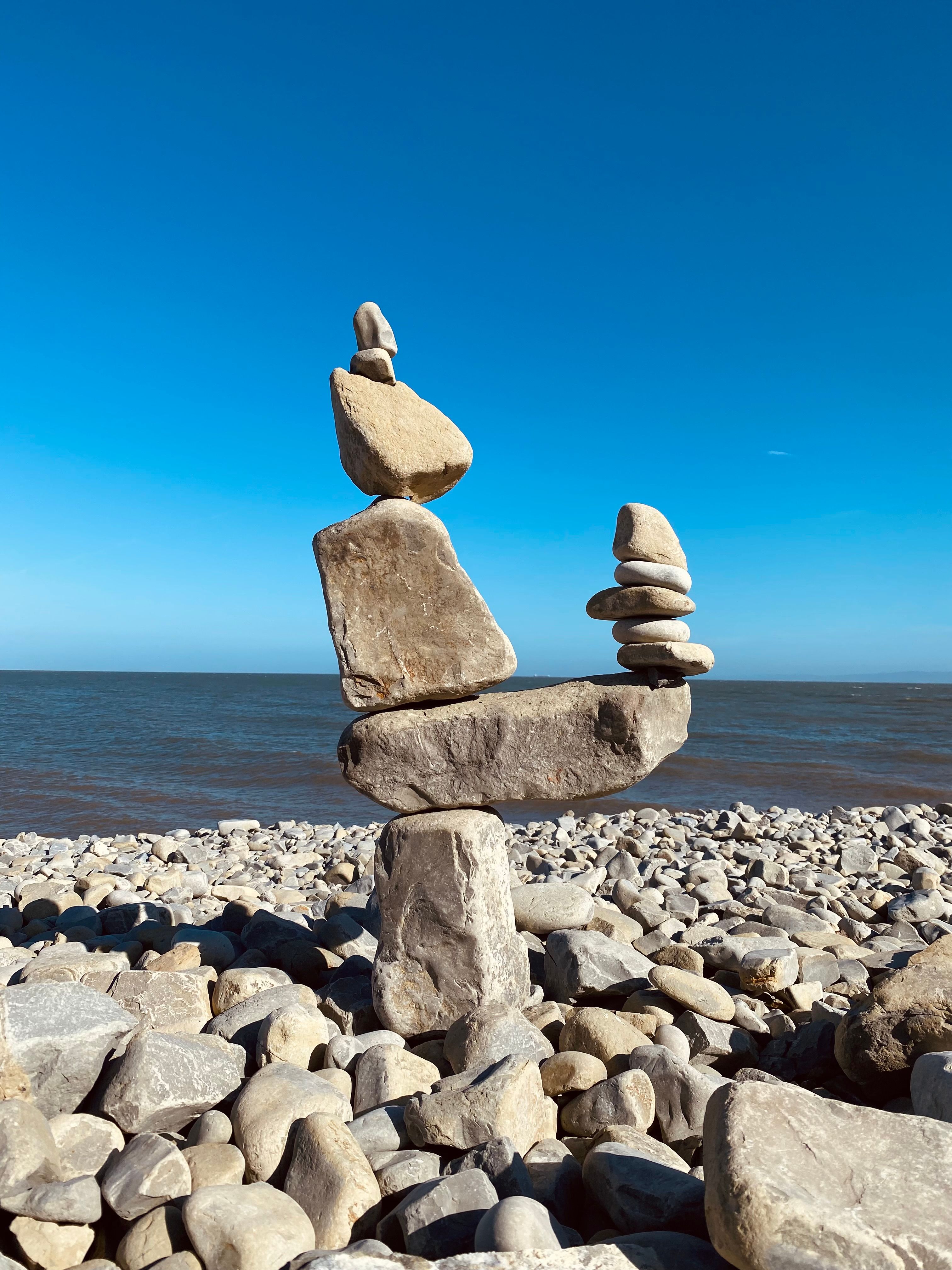 Balanced Rock Cairn on a Pebble Beach under Blue Sky · Free Stock Photo