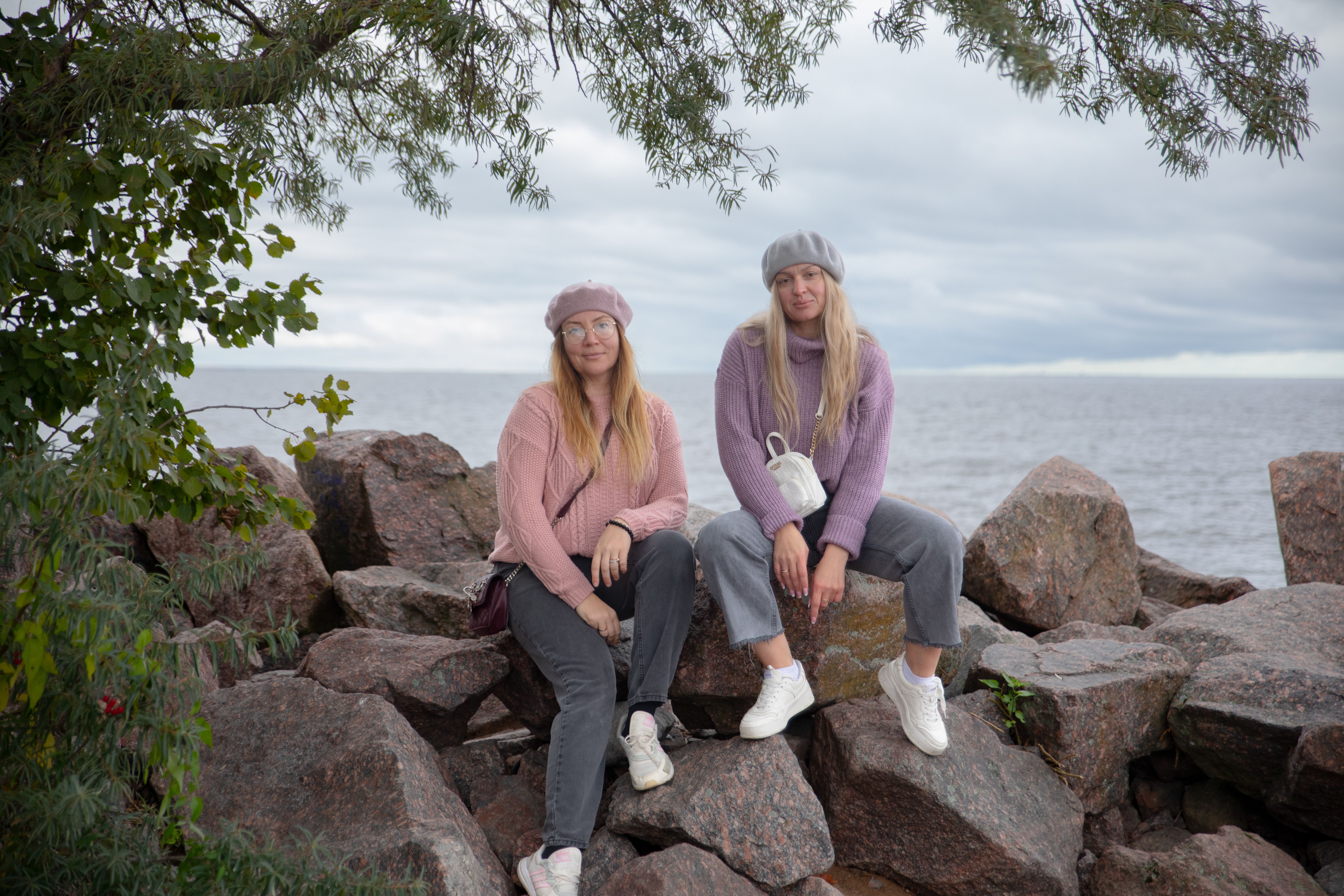 Two Women in Cozy Sweaters by Rocky Shoreline · Free Stock Photo