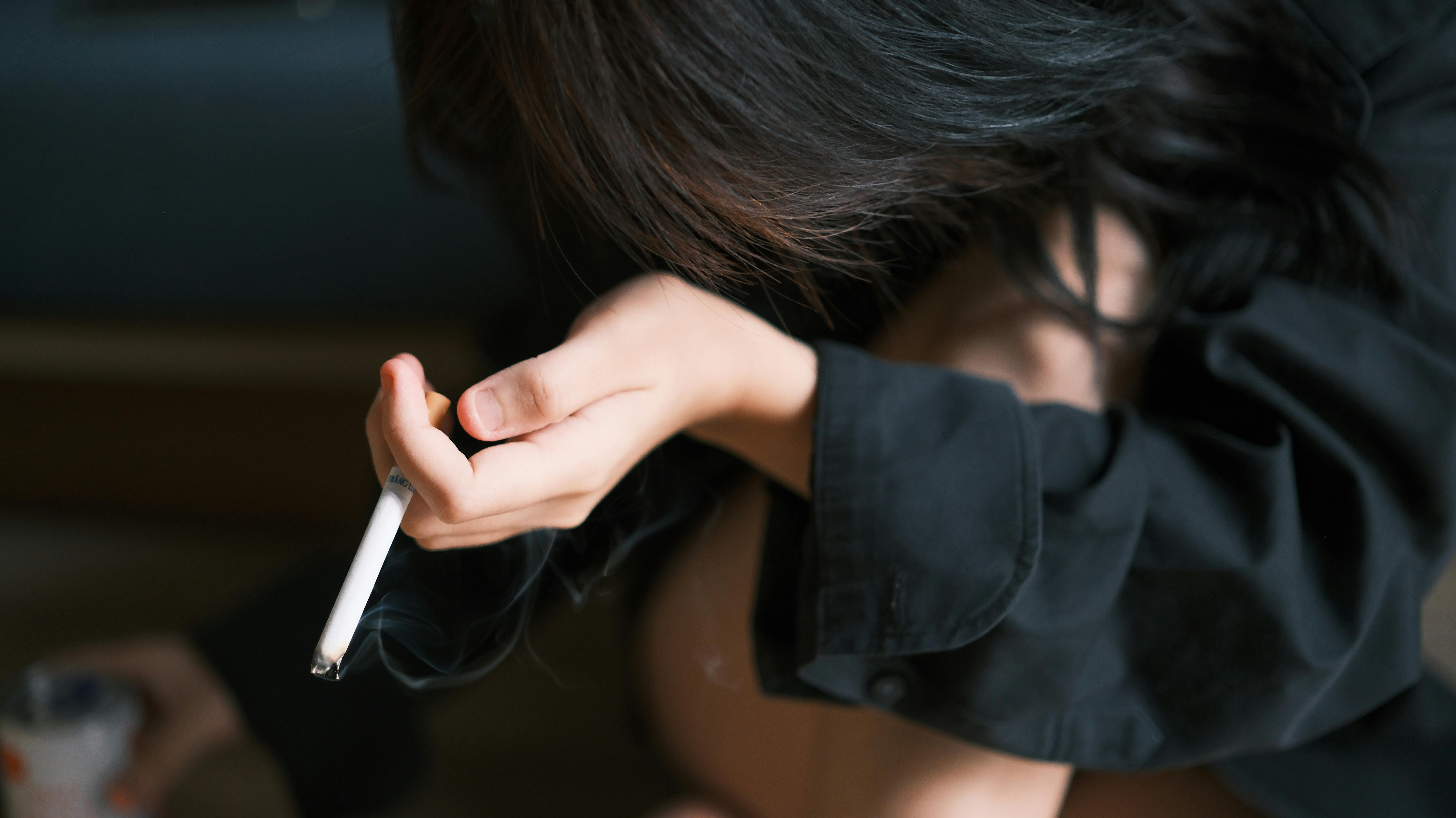 Young Woman Holding Cigarette Indoors · Free Stock Photo