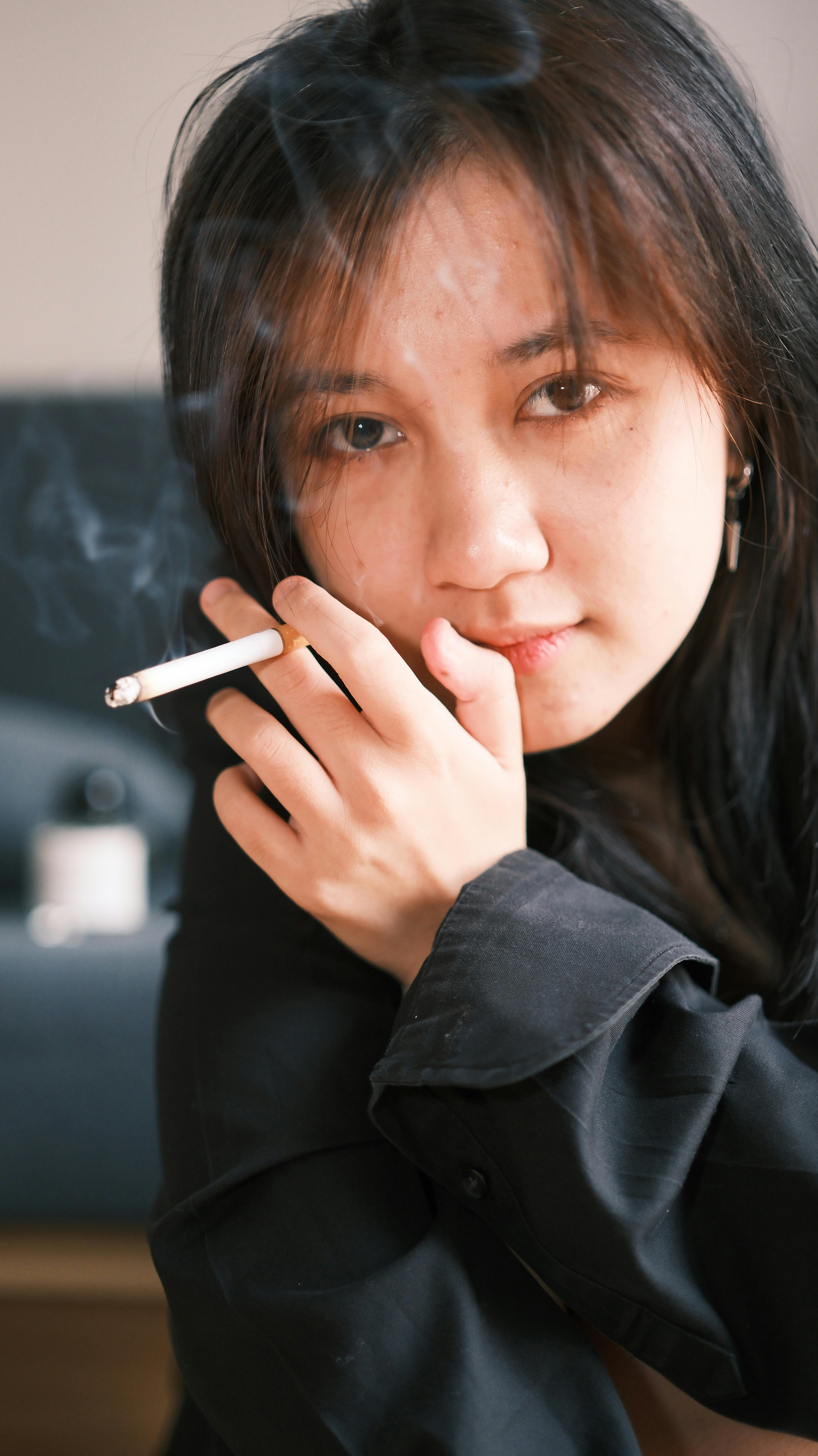 Woman Smoking Indoors with Relaxed Expression · Free Stock Photo