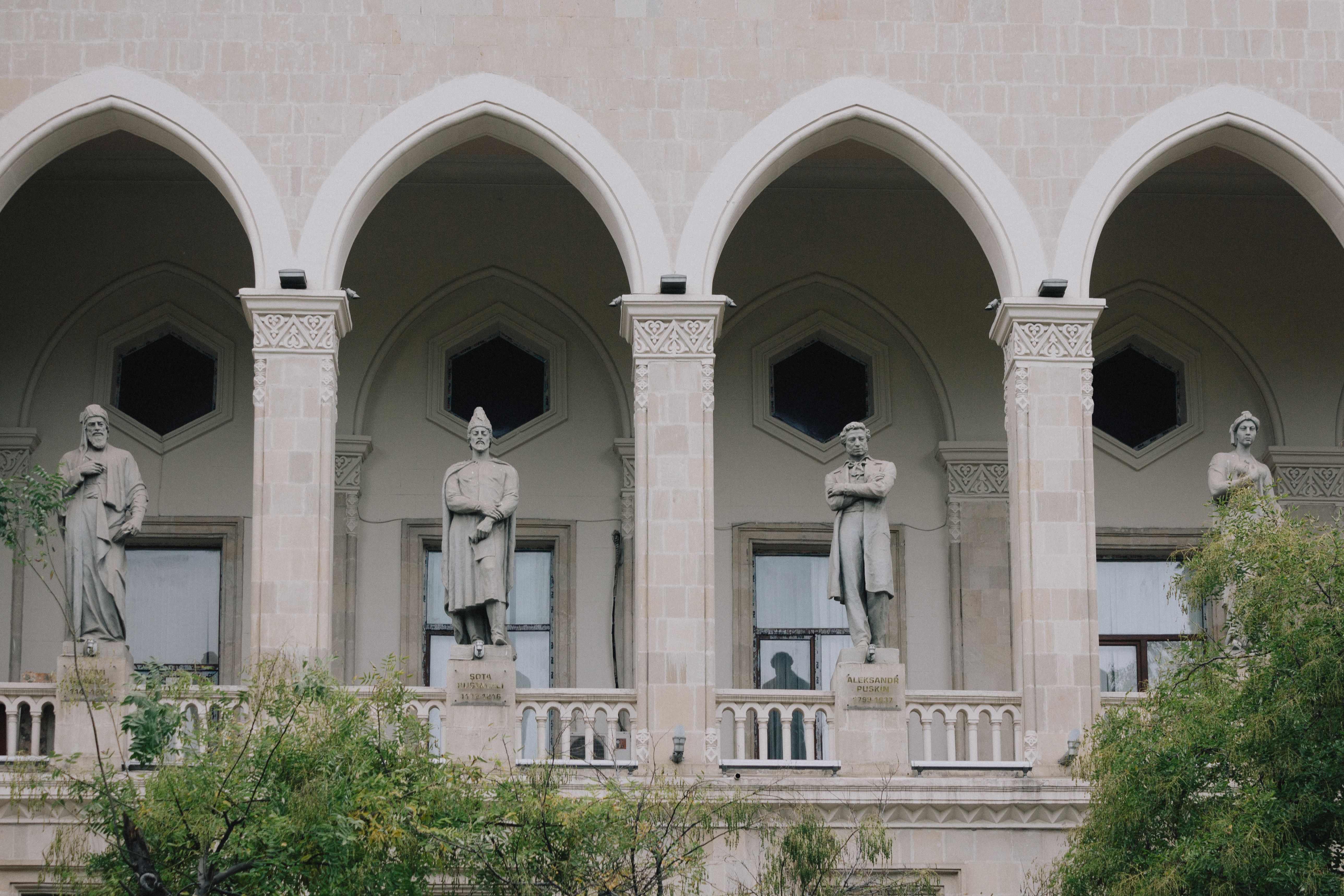 Historic Stone Statues on Arched Building Facade · Free Stock Photo