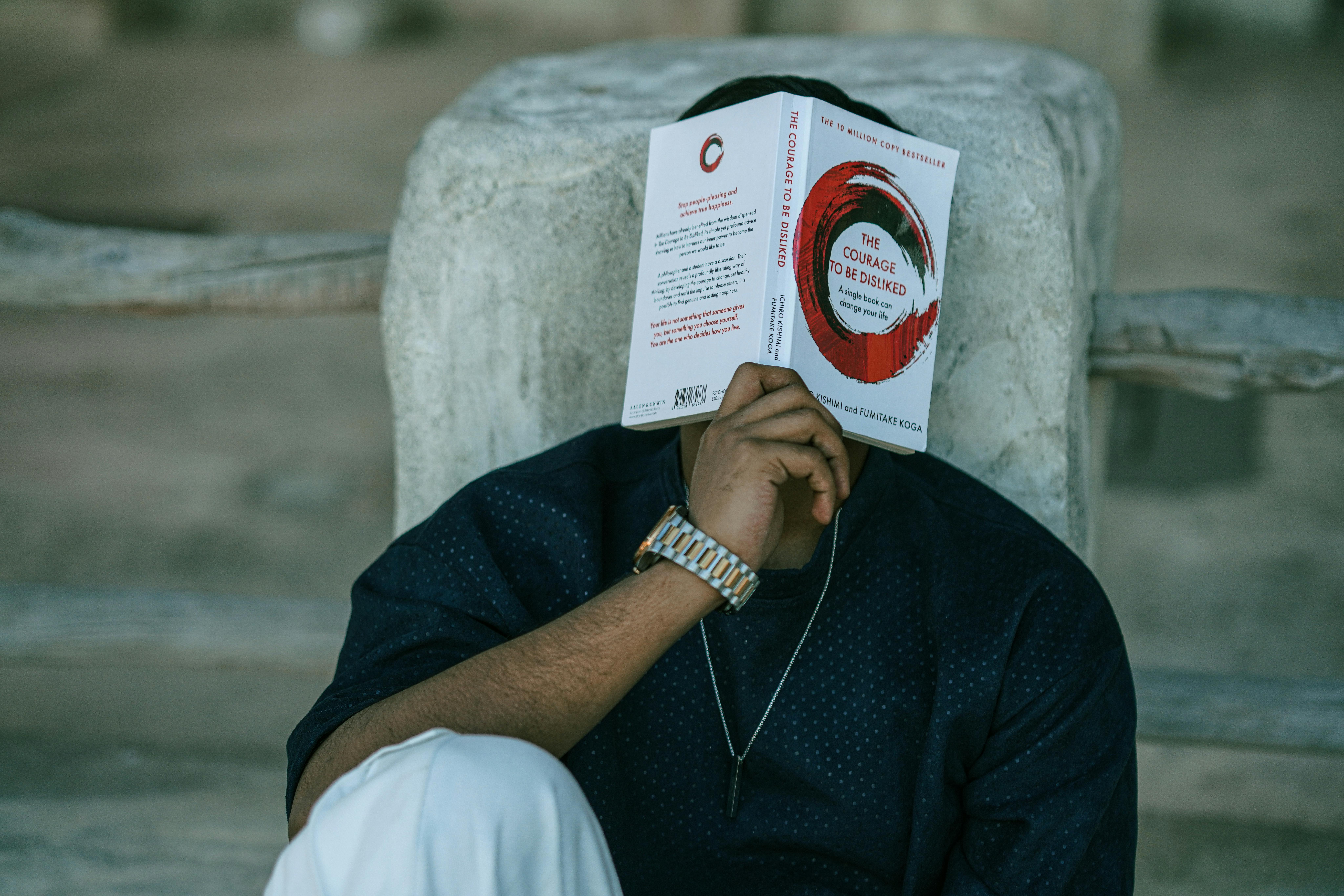 Man Reading "The Courage to Be Disliked" Outdoors · Free Stock Photo