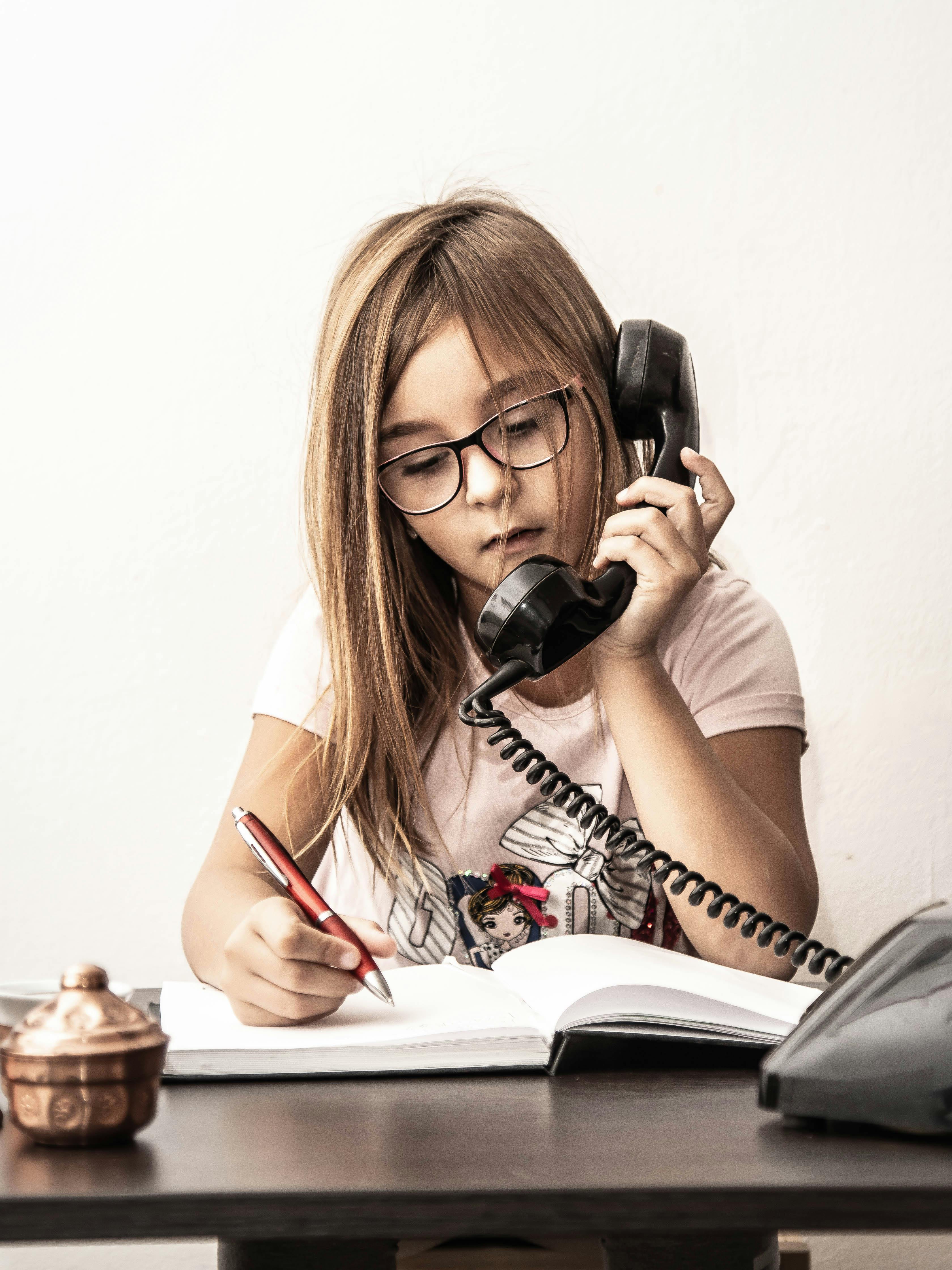 Young Girl on Retro Phone Writing Notes · Free Stock Photo
