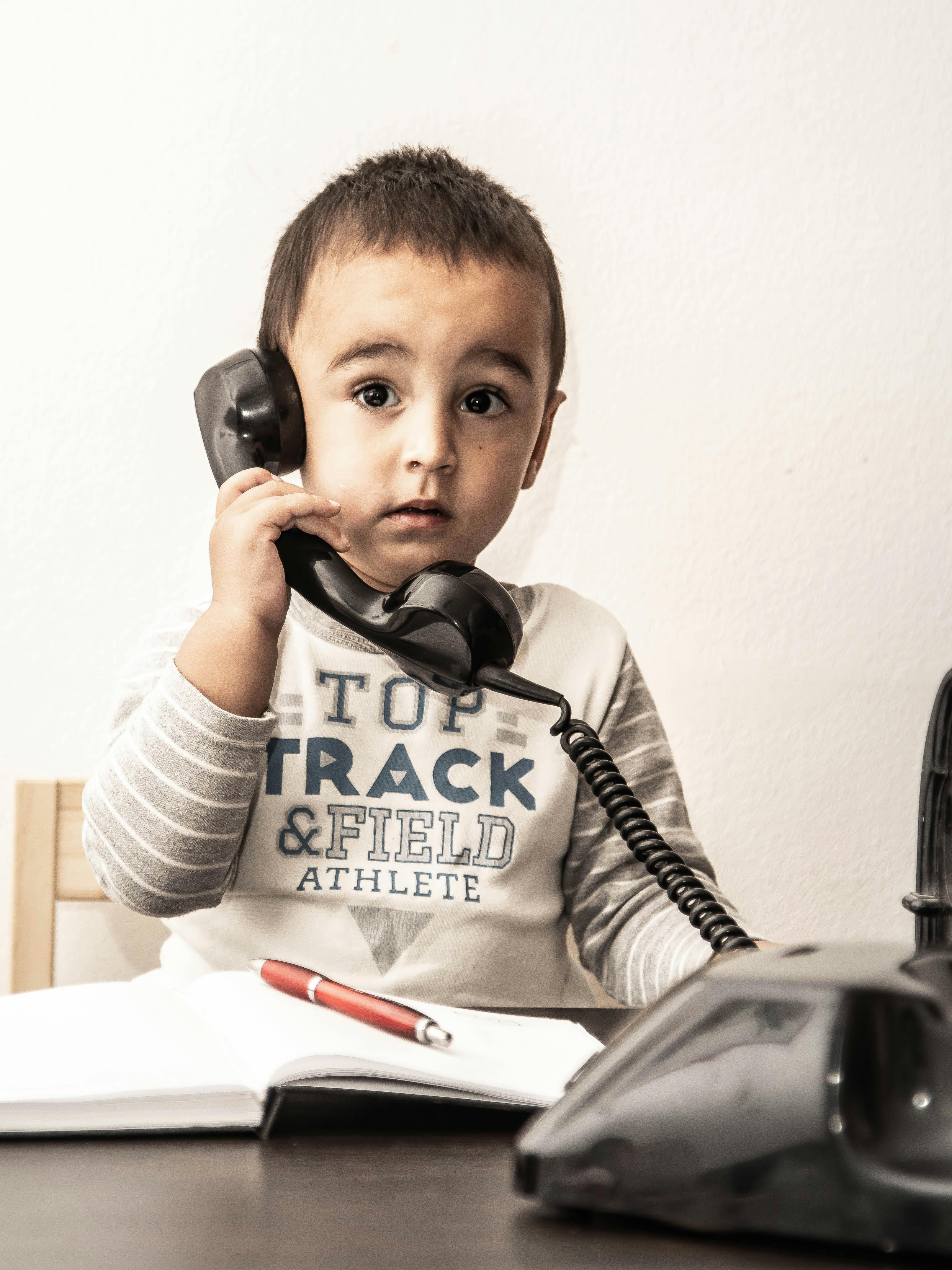 Cute Child Talking on Vintage Telephone Indoors · Free Stock Photo