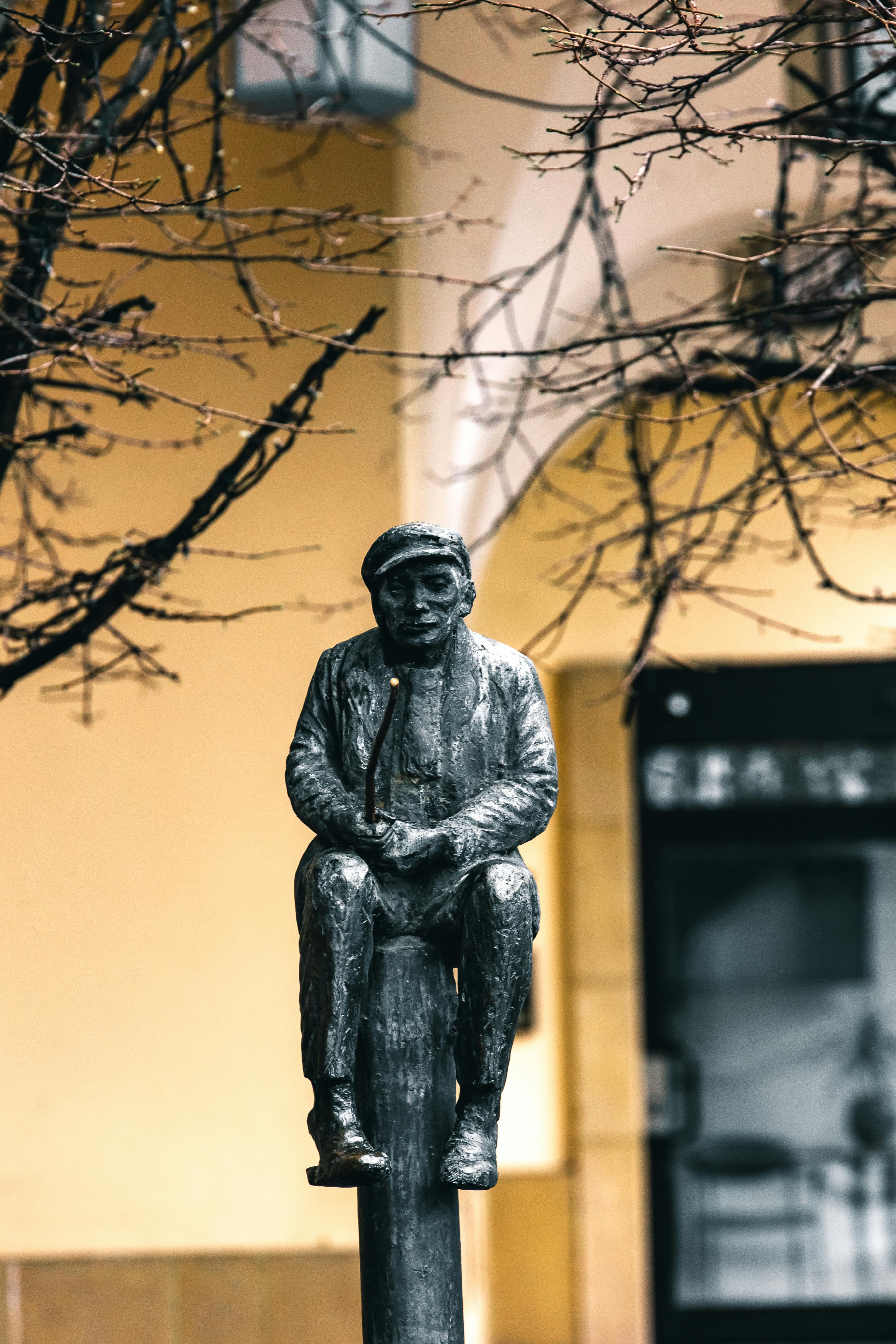Street statue of seated man in winter setting · Free Stock Photo