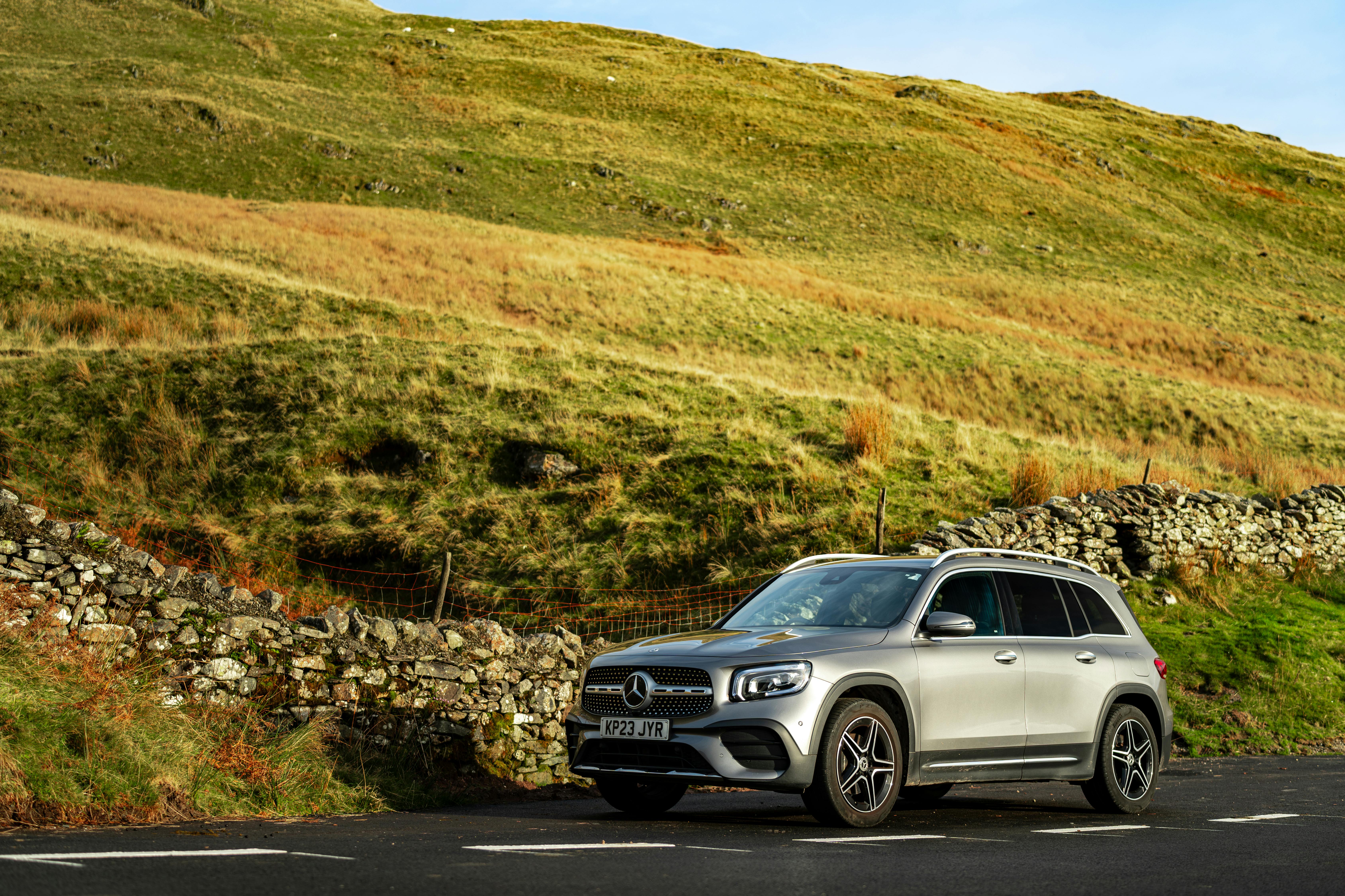 Silver SUV Parked by Scenic Stone Wall Landscape · Free Stock Photo