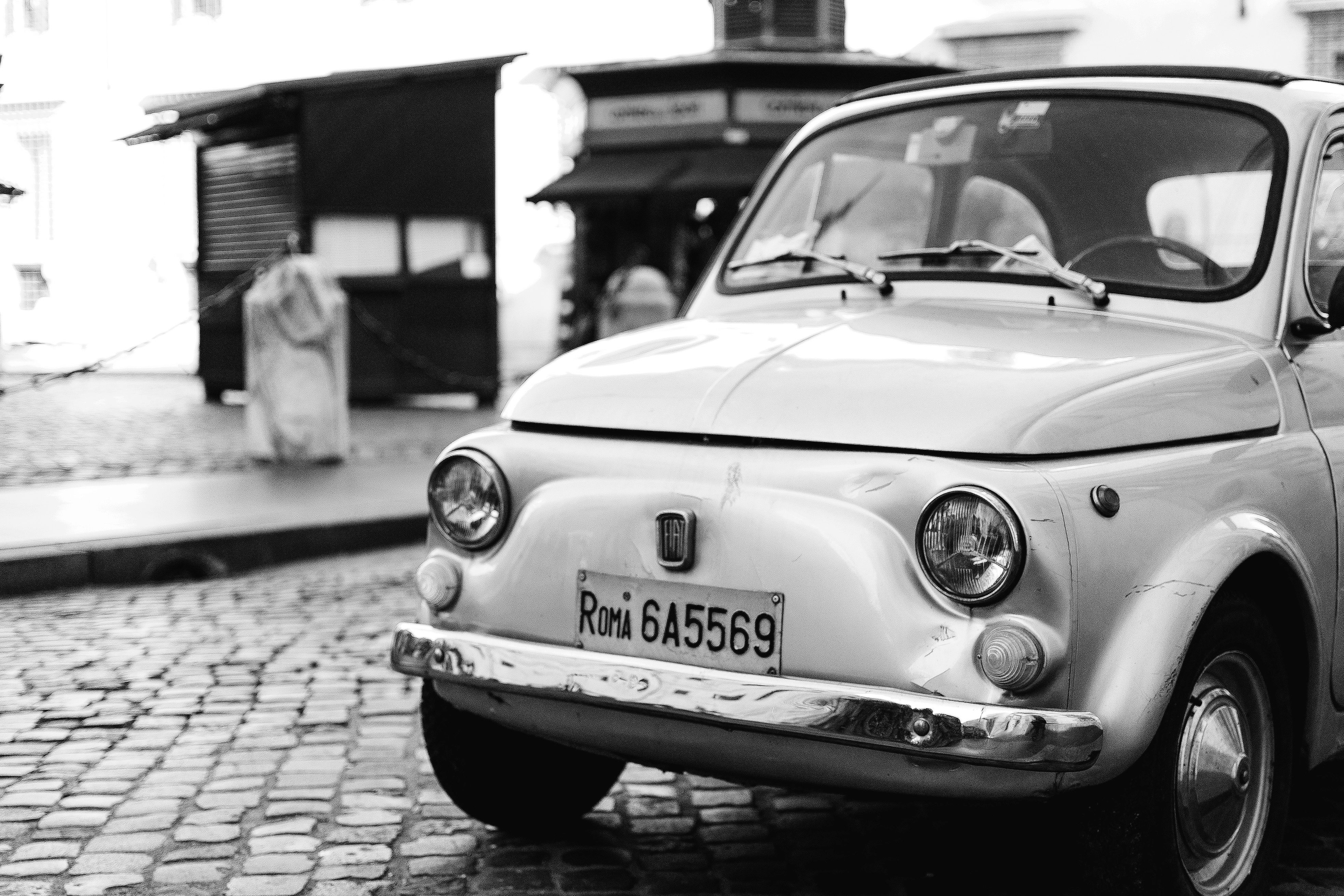 Vintage Fiat parked on cobblestone street · Free Stock Photo