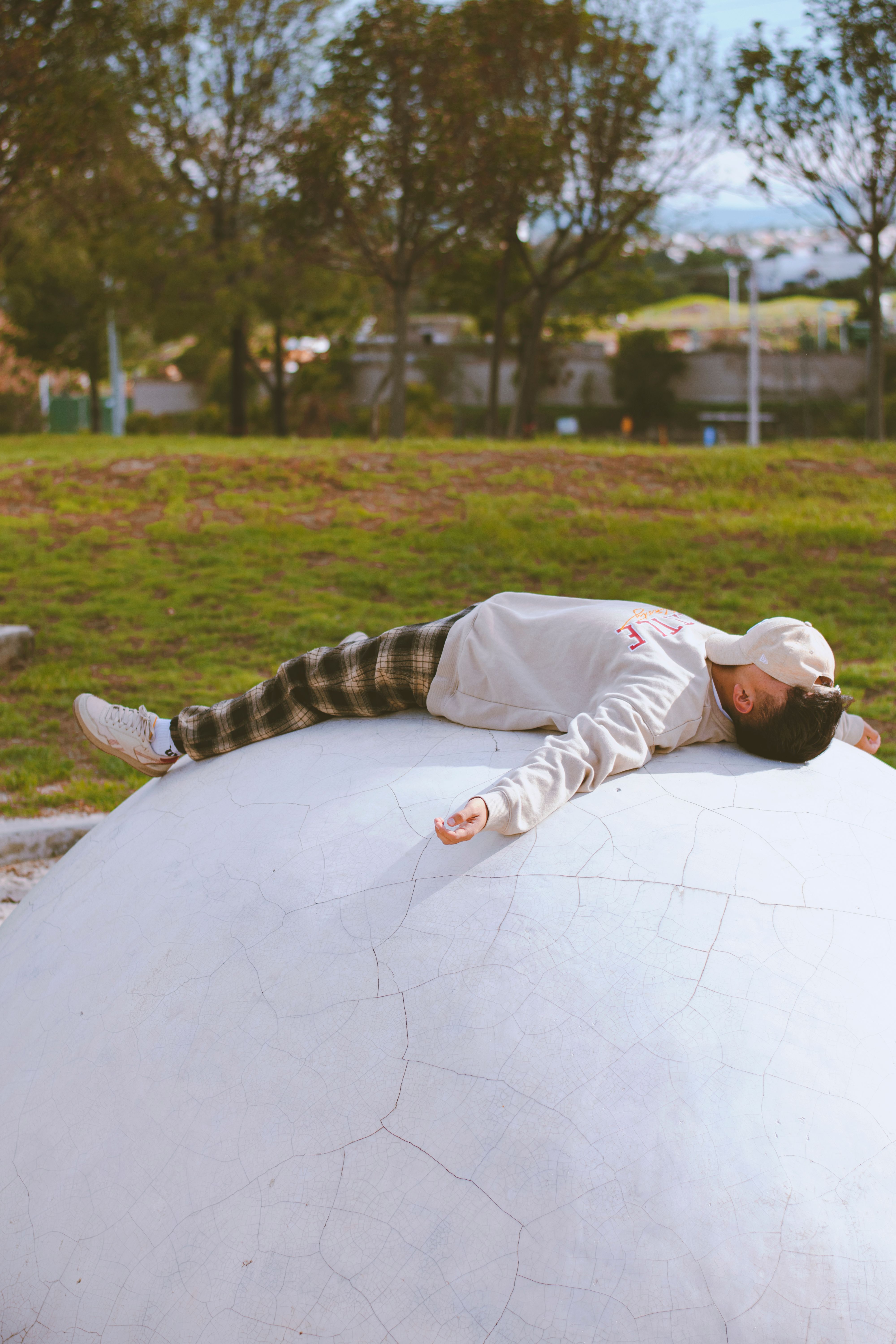 Relaxed Young Man Resting Outdoors on Sculpture · Free Stock Photo