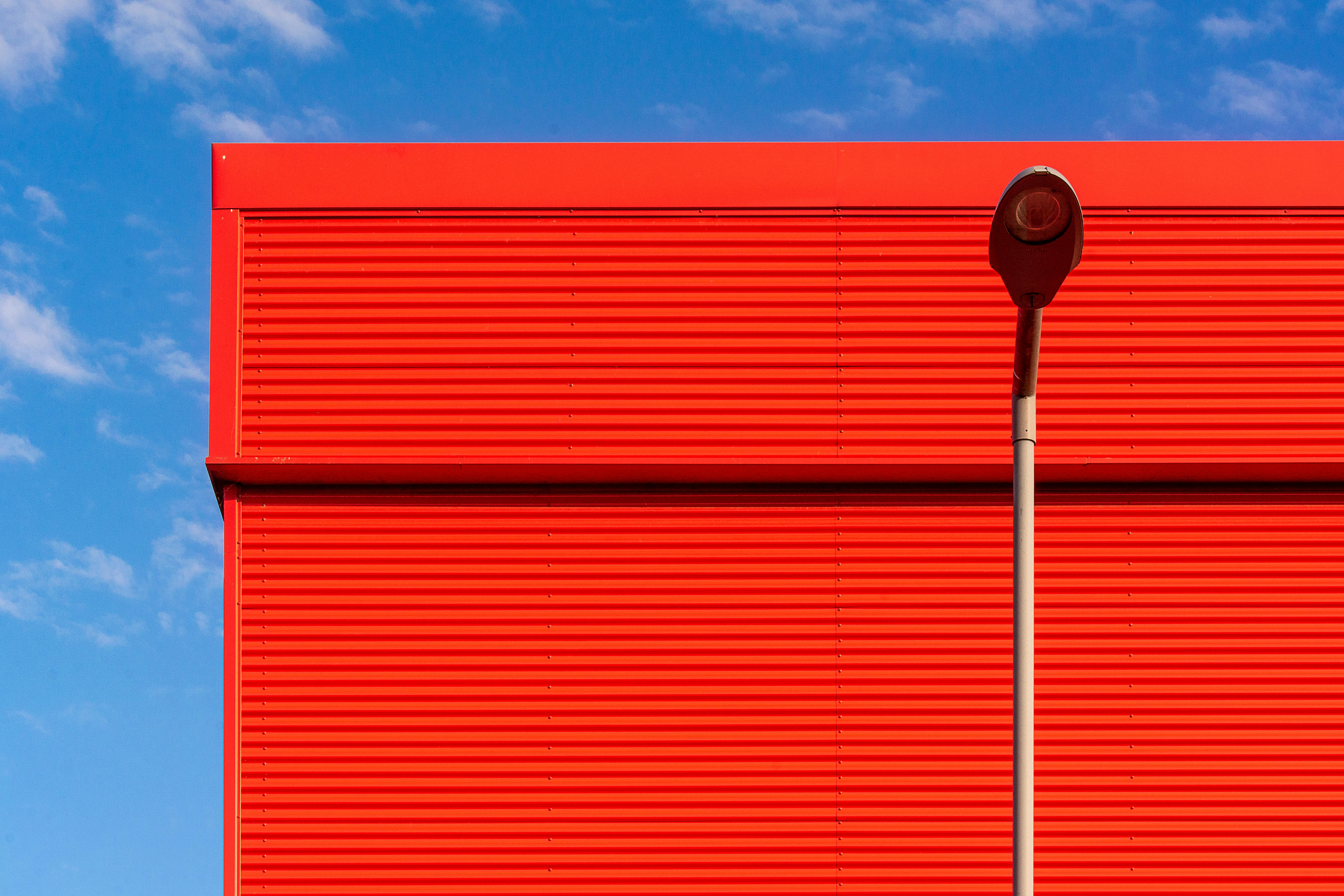 Red Building Facade with Street Lamp Against Blue Sky · Free Stock Photo