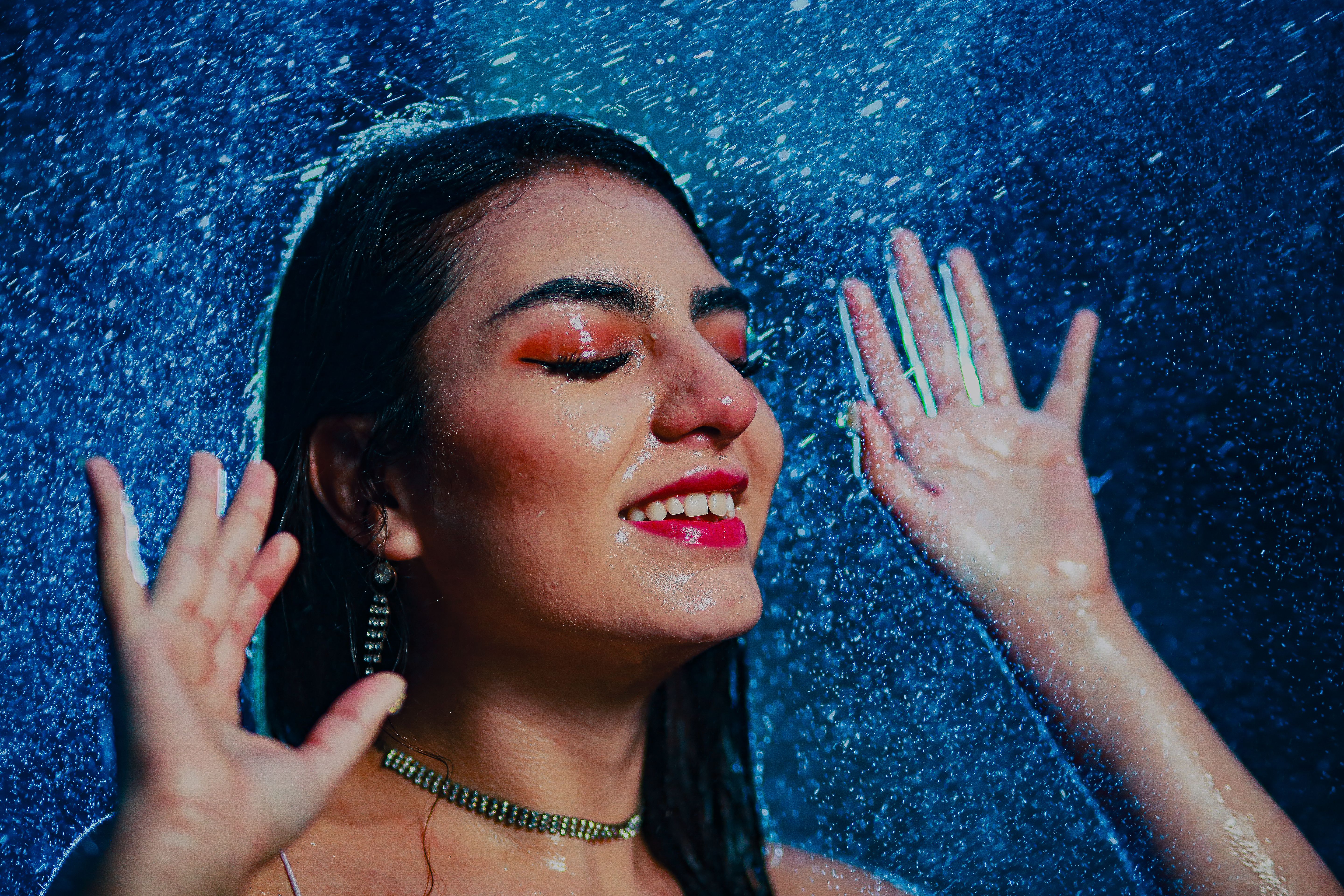 Joyful Woman Enjoying Rain in Vibrant Portrait · Free Stock Photo
