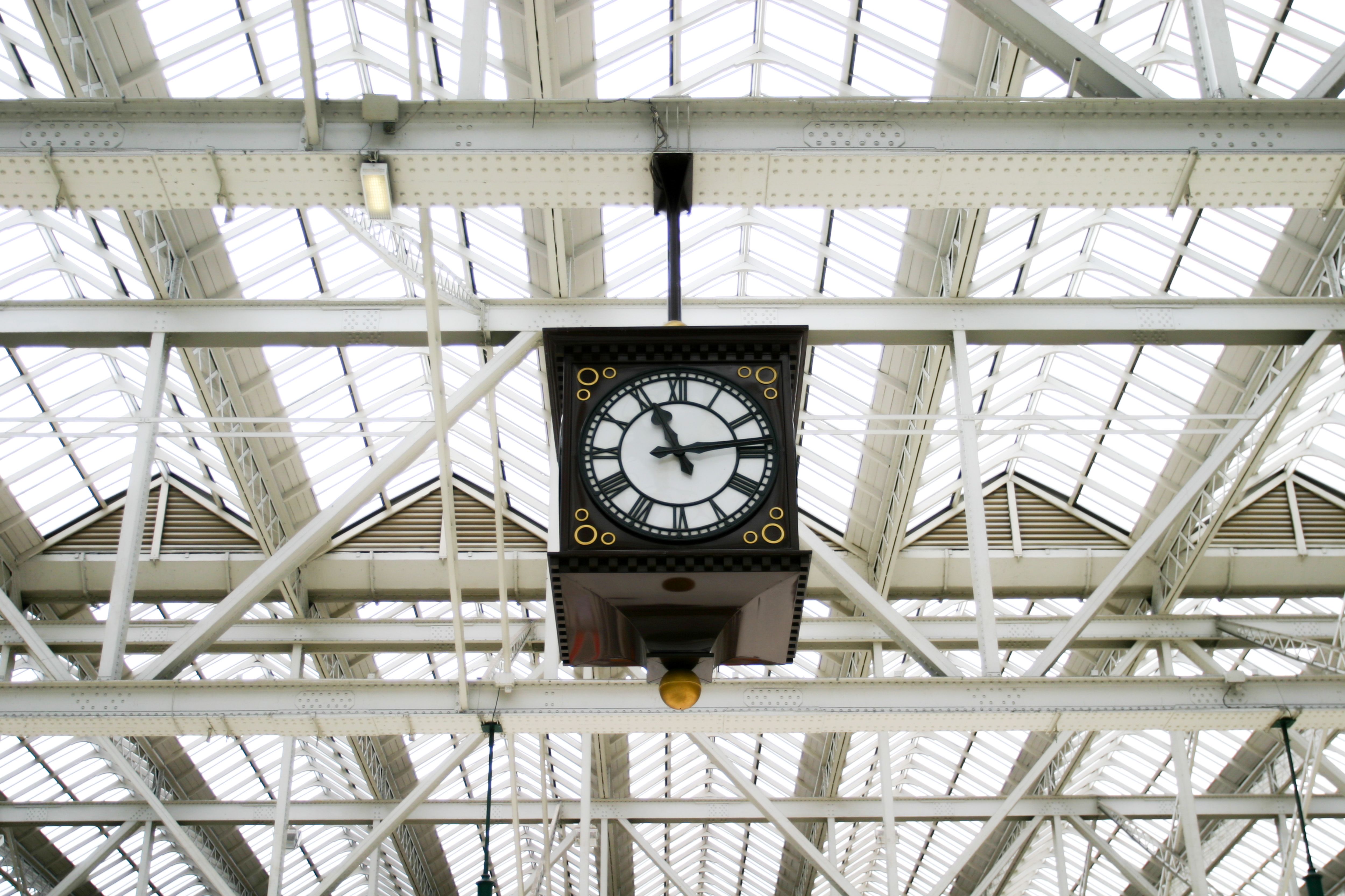 Railway station clock under glass roof · Free Stock Photo