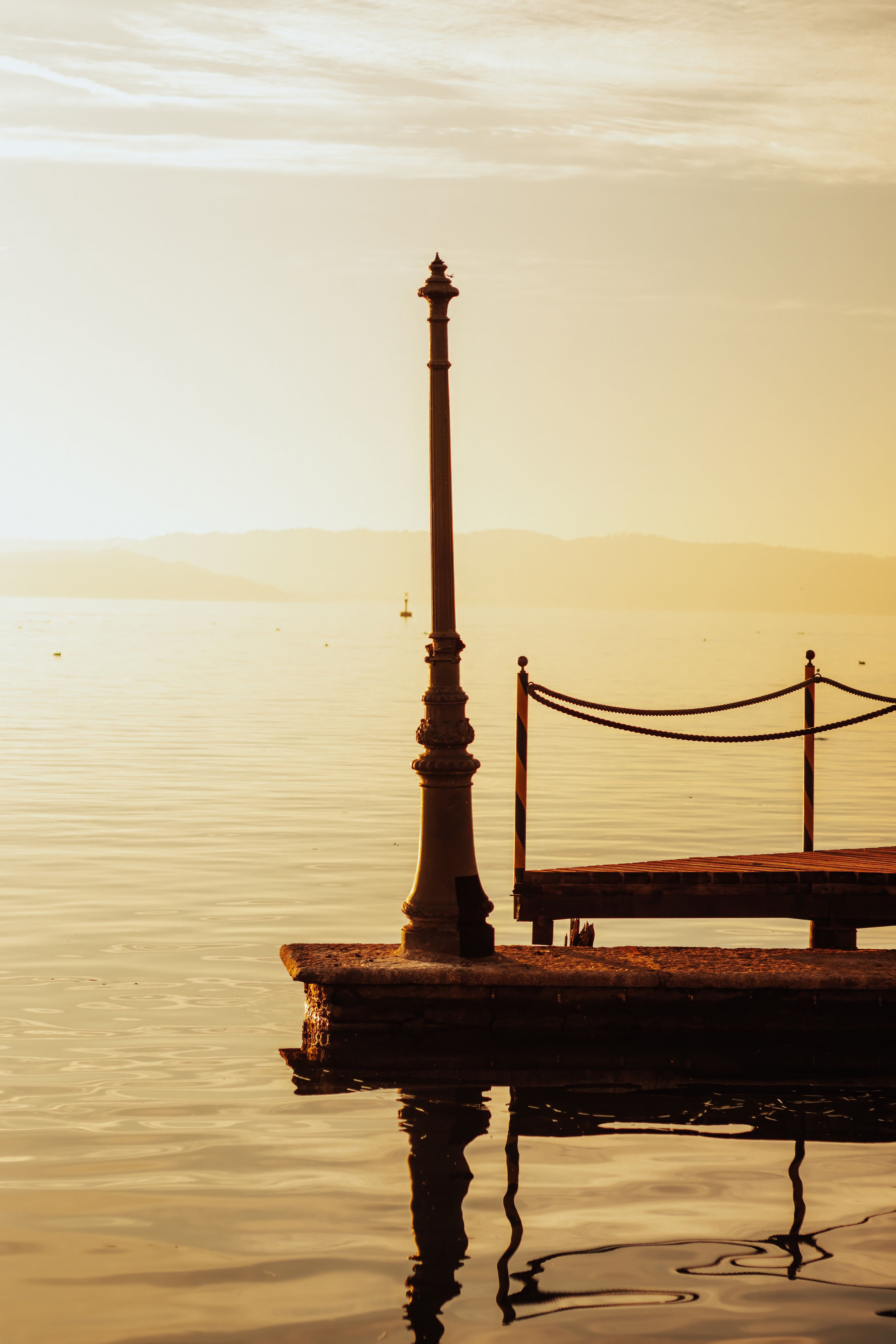 Serene Waterfront at Sunset with Lamp Post · Free Stock Photo
