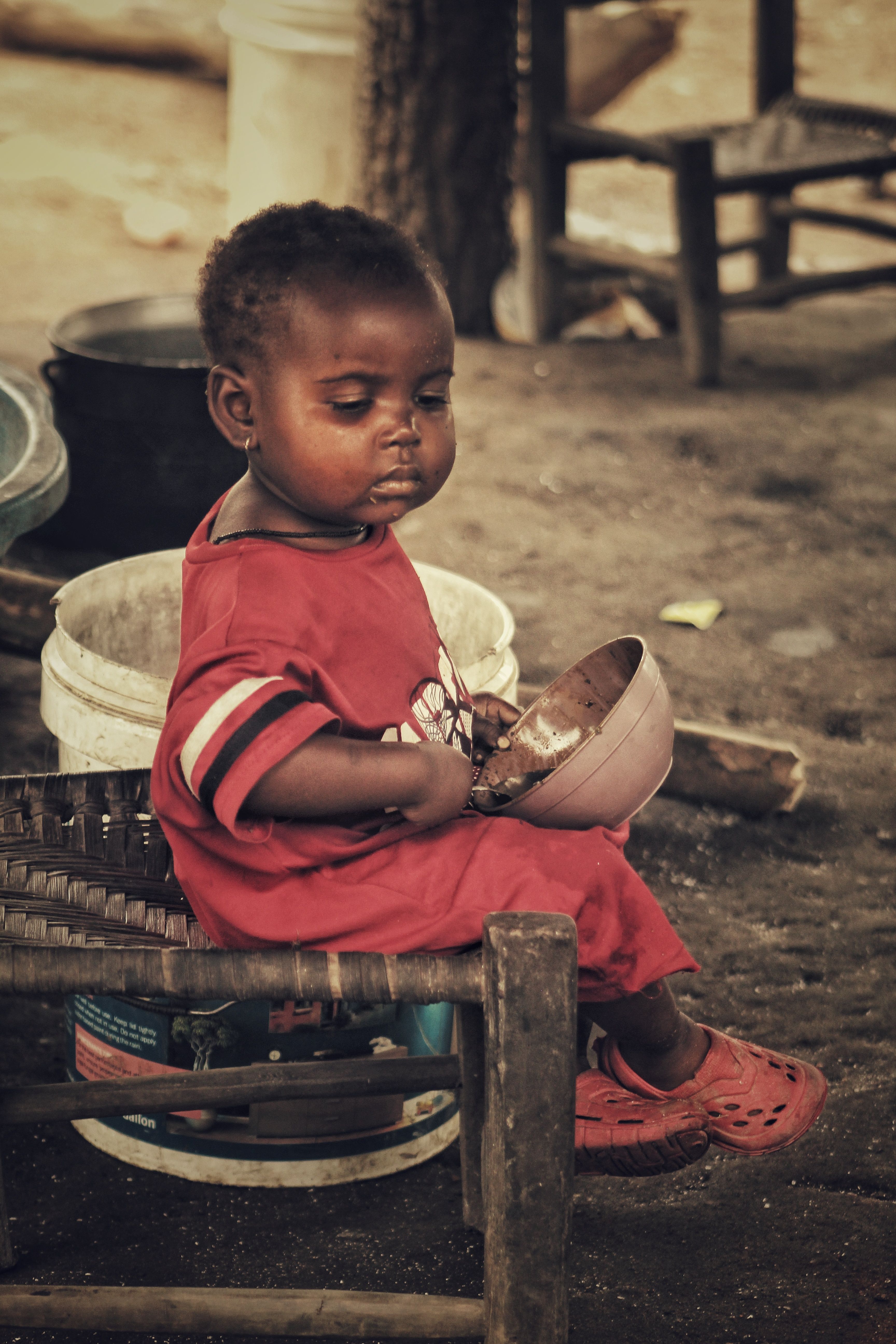 African Child Eating from Bowl Outdoors · Free Stock Photo