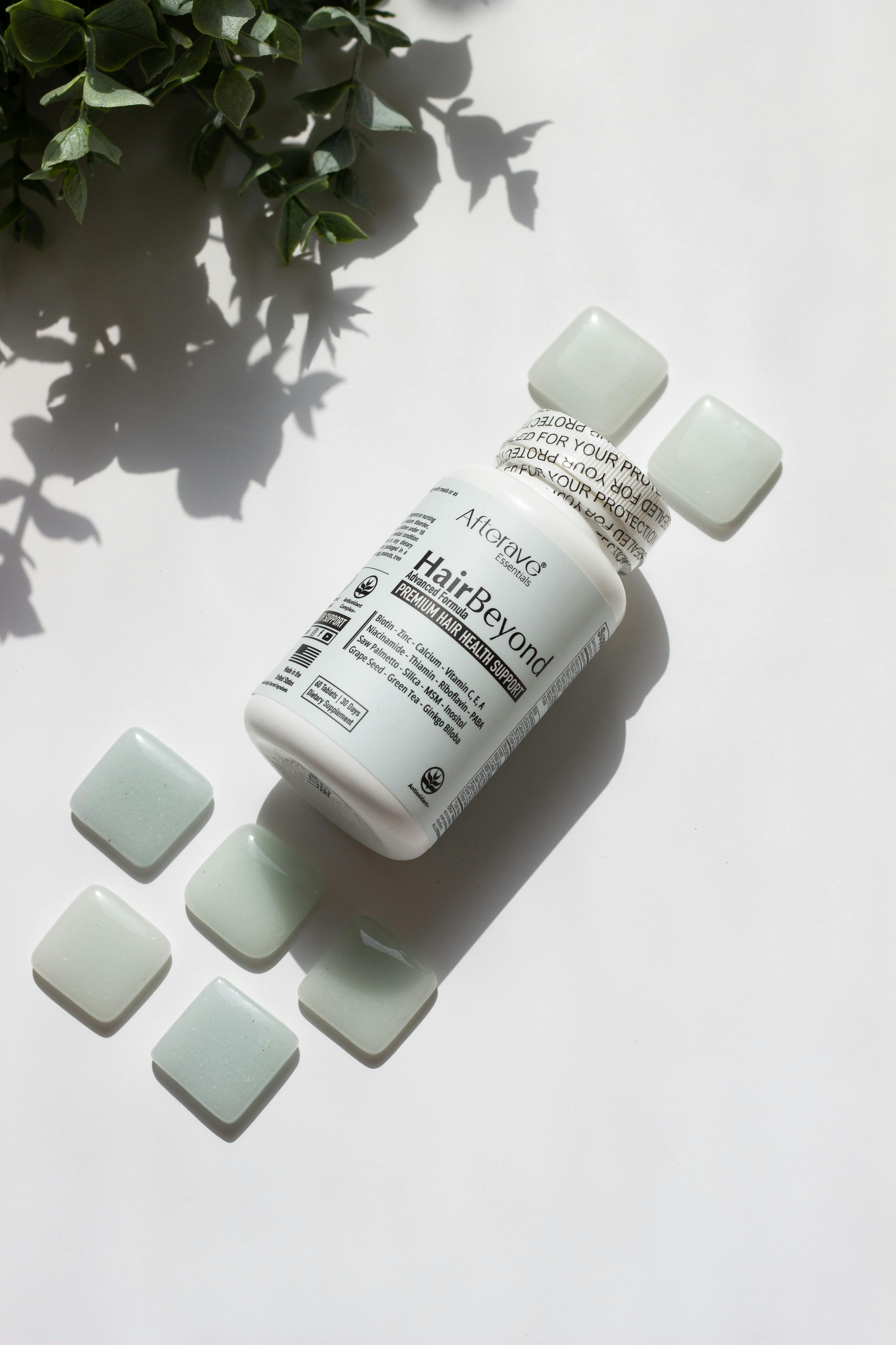 Hair Vitamins Bottle with Green Tablets on White Surface · Free Stock Photo