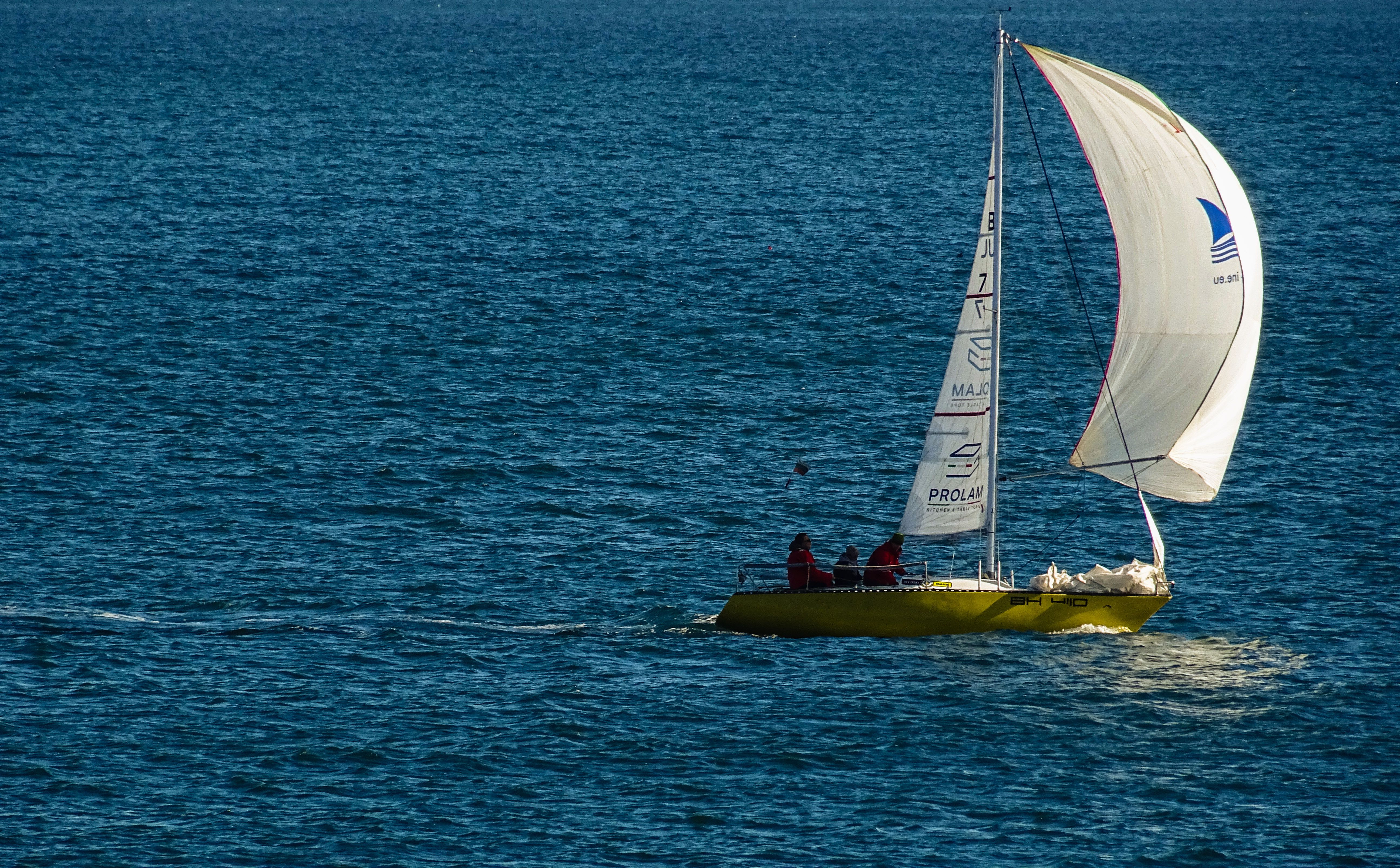 Sailboat floating in sea near rocky cliff · Free Stock Photo