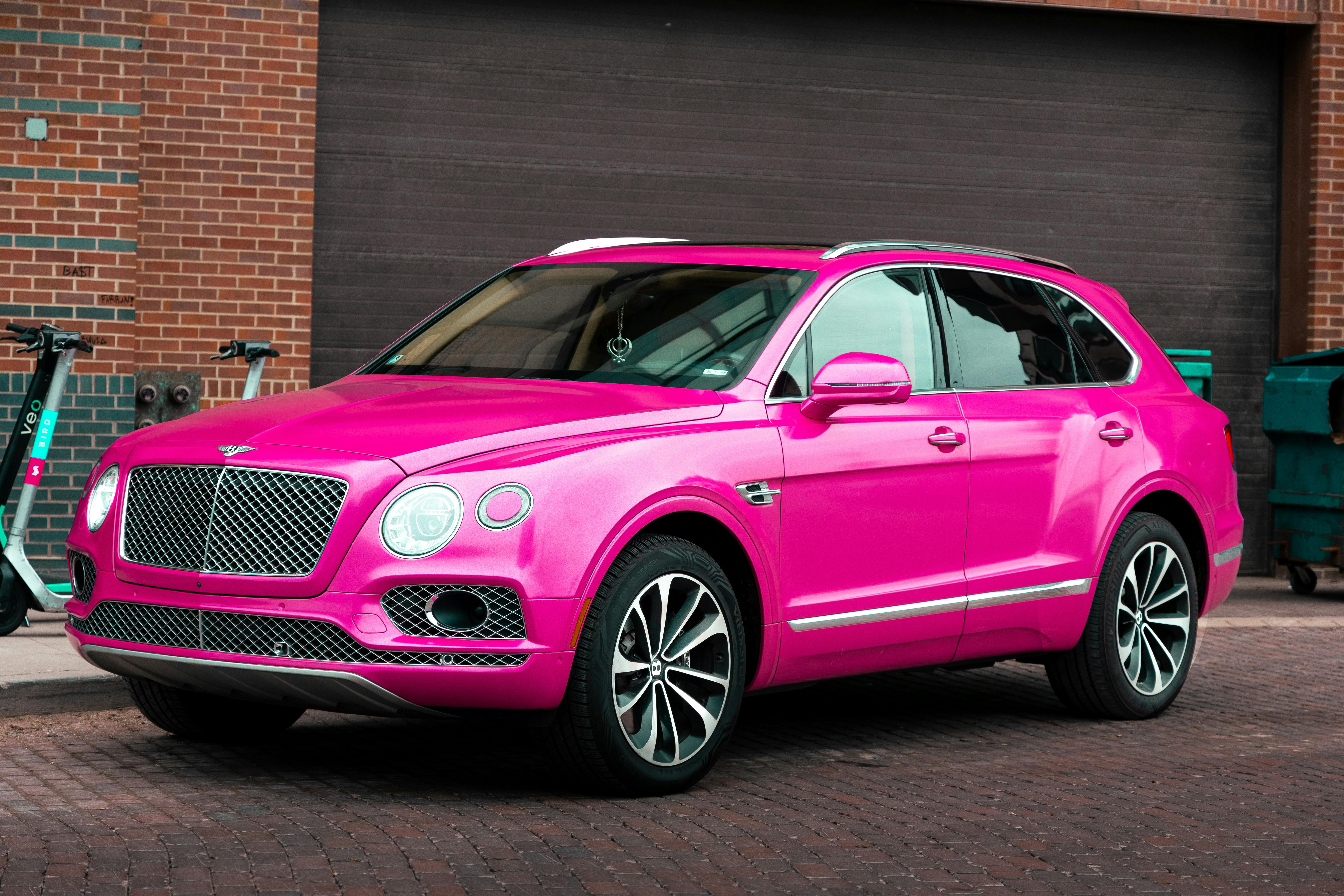 Vibrant Pink Luxury SUV Parked on Brick Street · Free Stock Photo