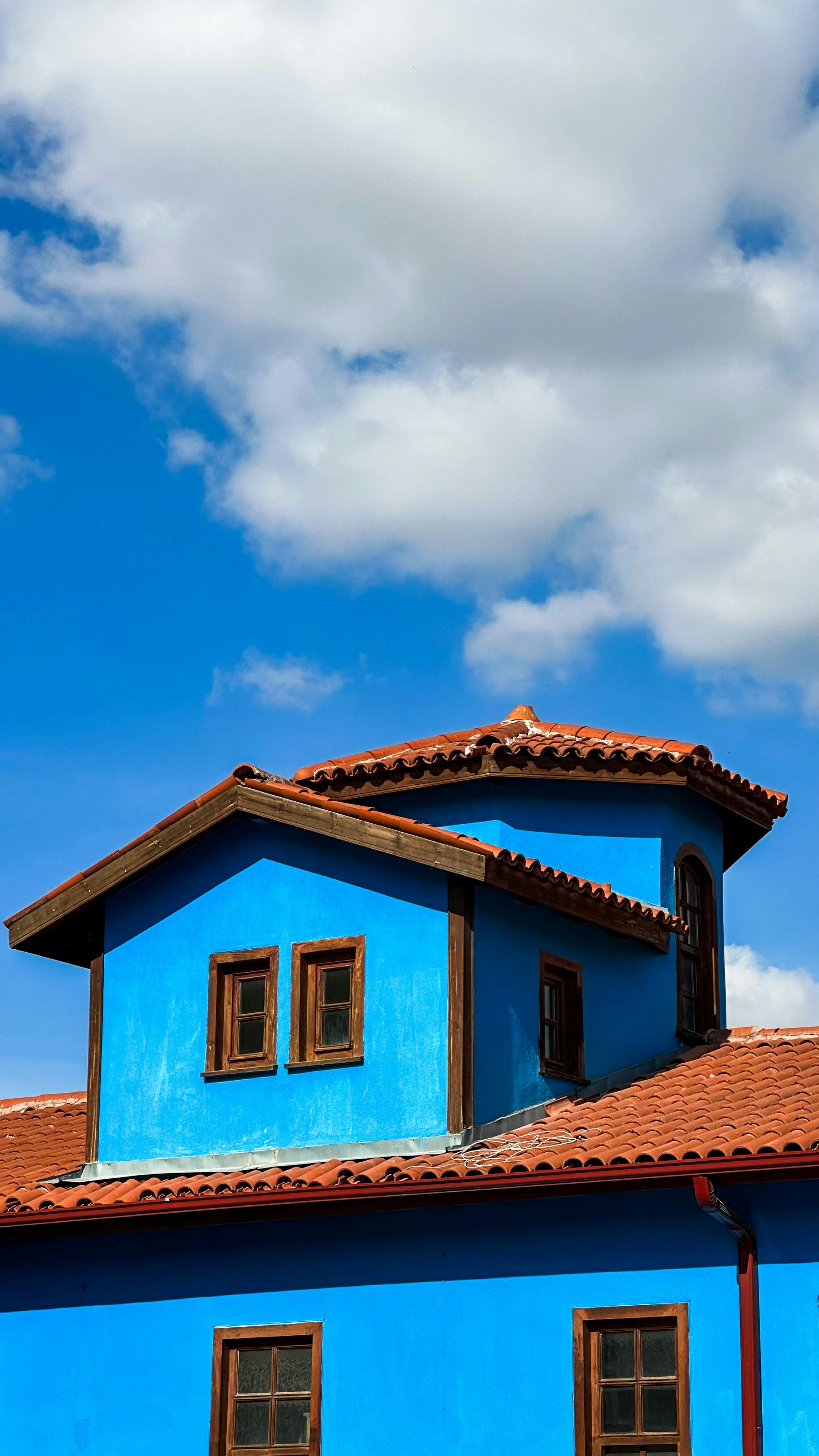 Vibrant Blue House with Rustic Red Roof Under Clear Sky · Free Stock Photo