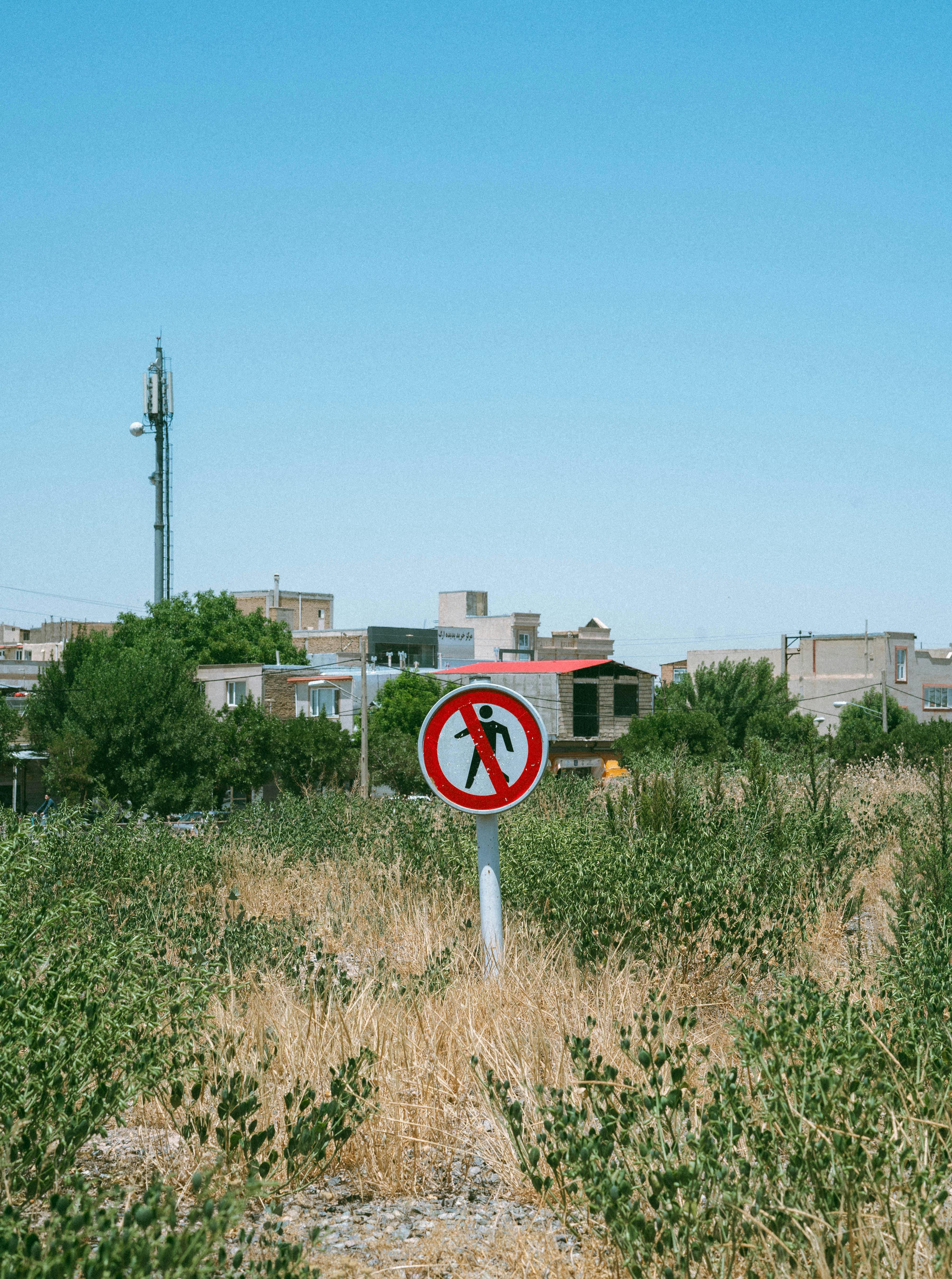 Outdoor Warning Sign in Grassy Field near Town · Free Stock Photo