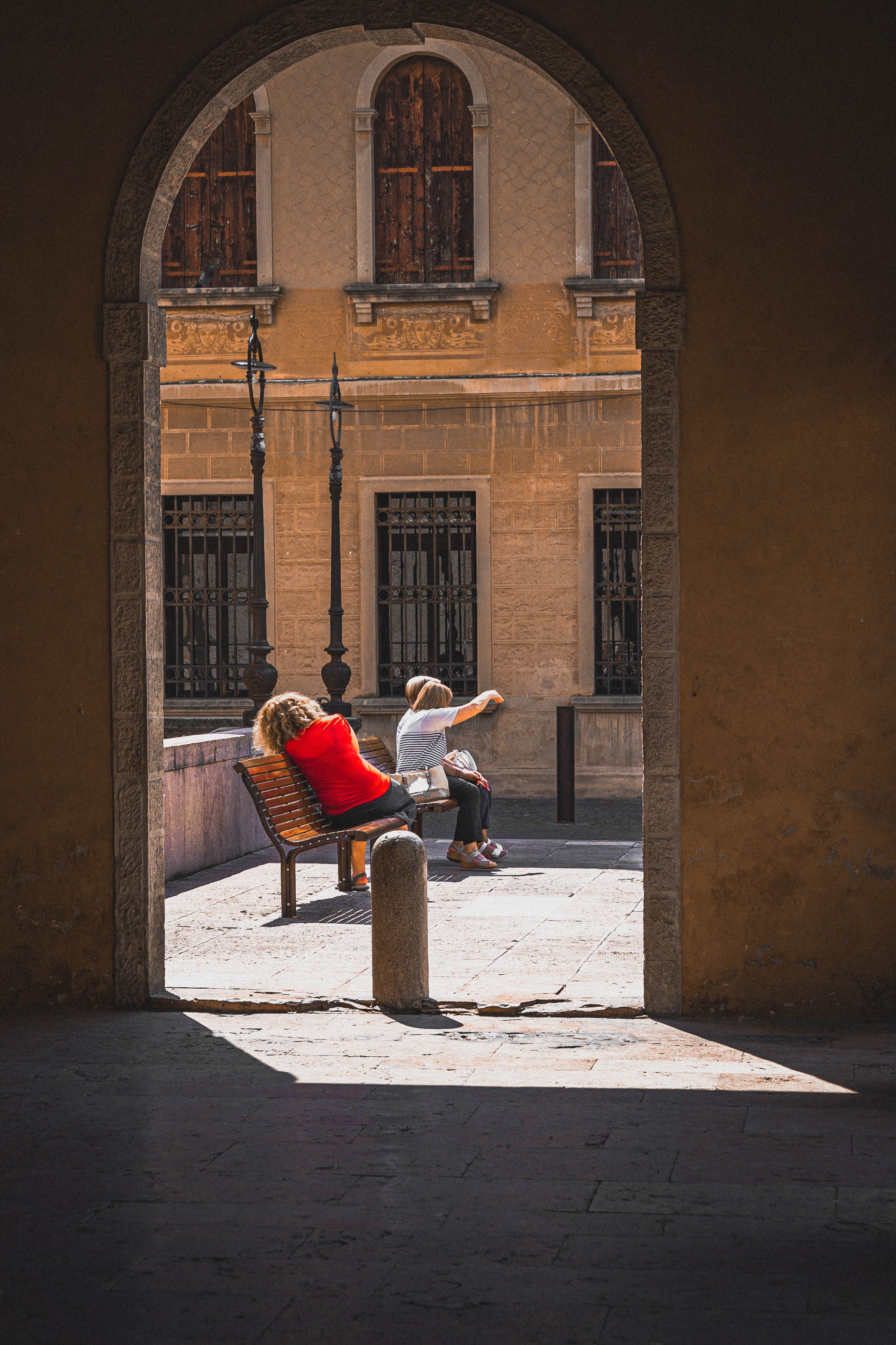 Two People Relaxing on Bench in Historic Plaza · Free Stock Photo
