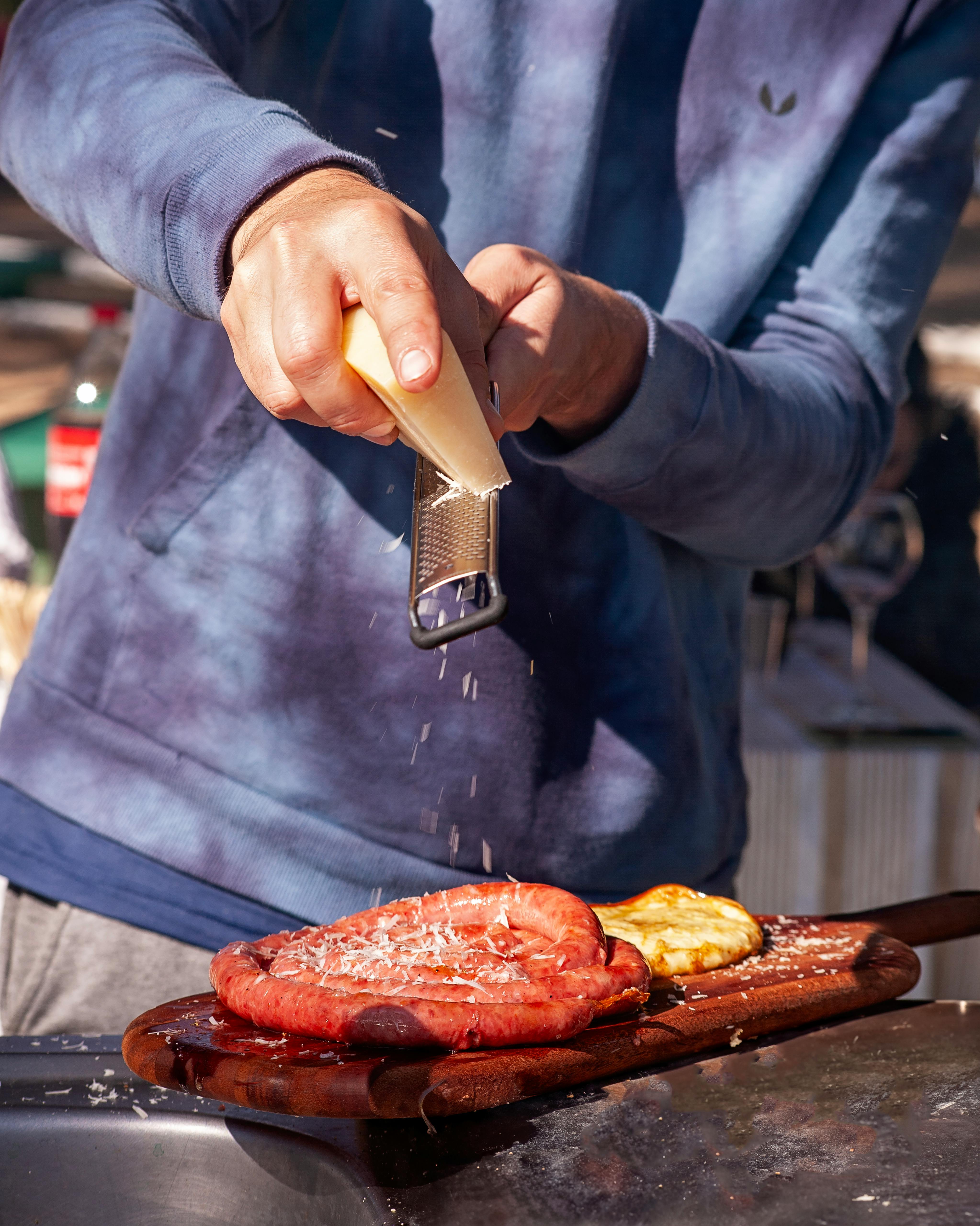Man Grating Cheese Over Delicious BBQ Dish · Free Stock Photo