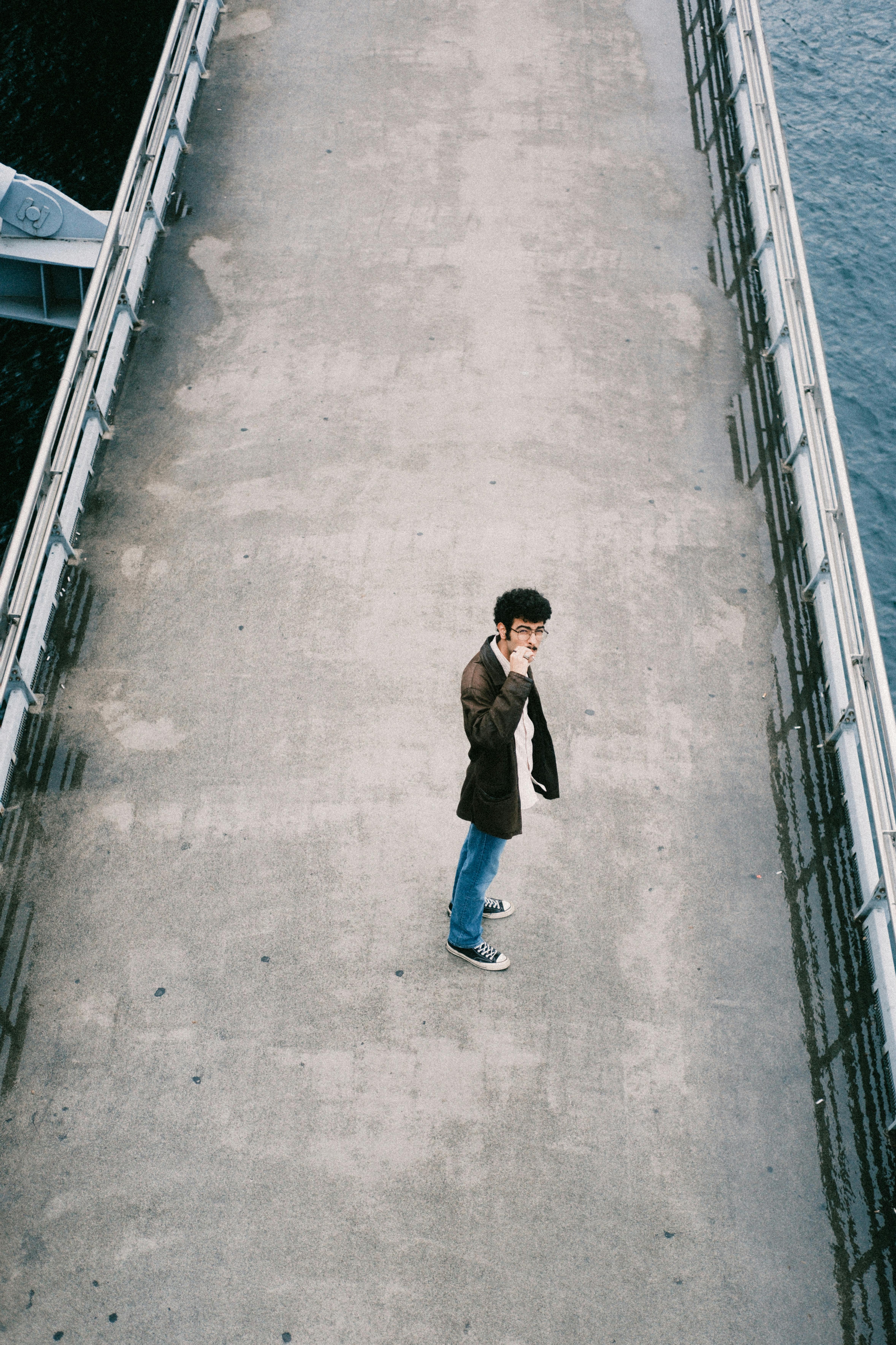 Man standing on bridge with ocean view · Free Stock Photo