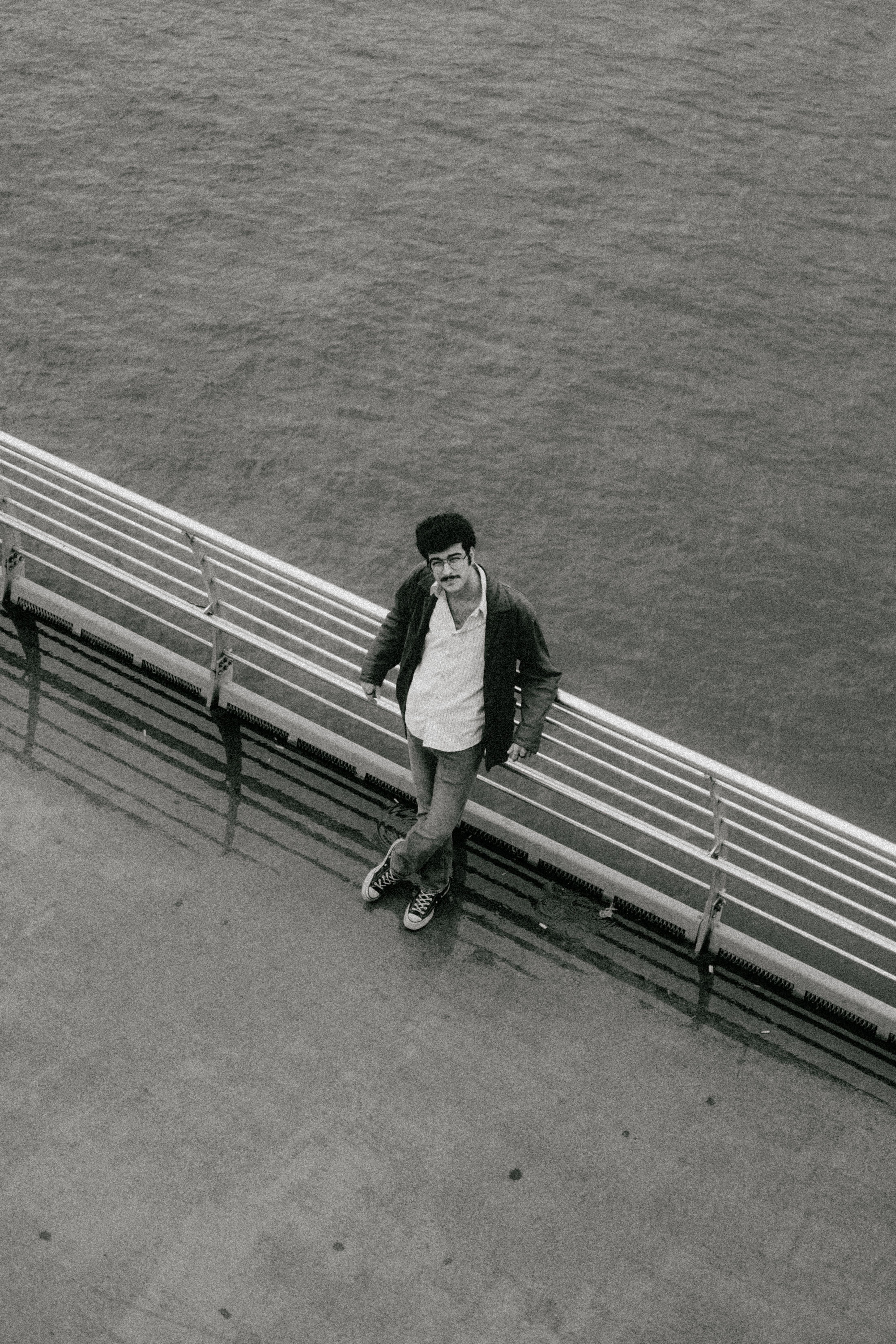 Man Leaning Against Railing Overlooking Water · Free Stock Photo