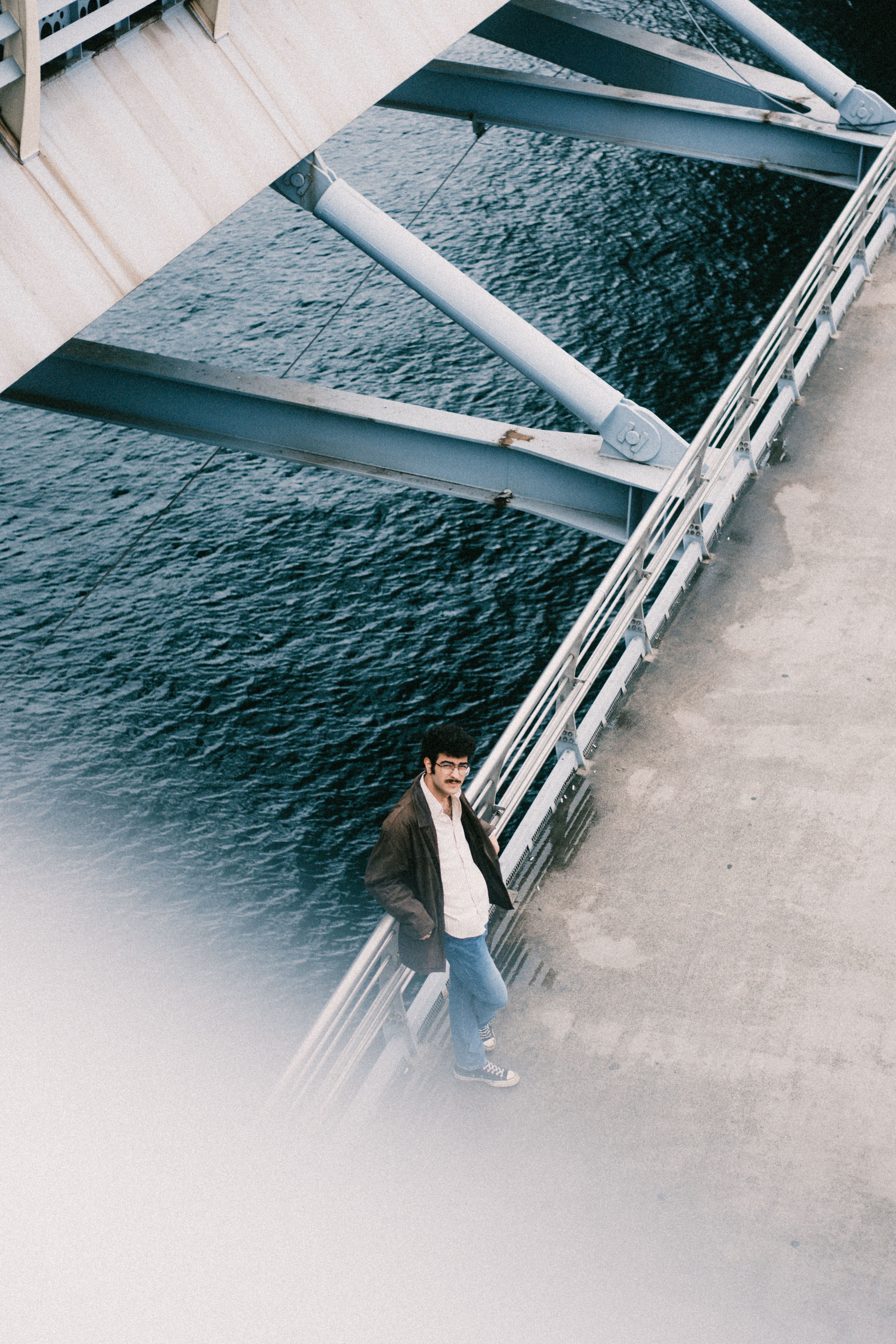Man Standing on Bridge Overlooking Water · Free Stock Photo