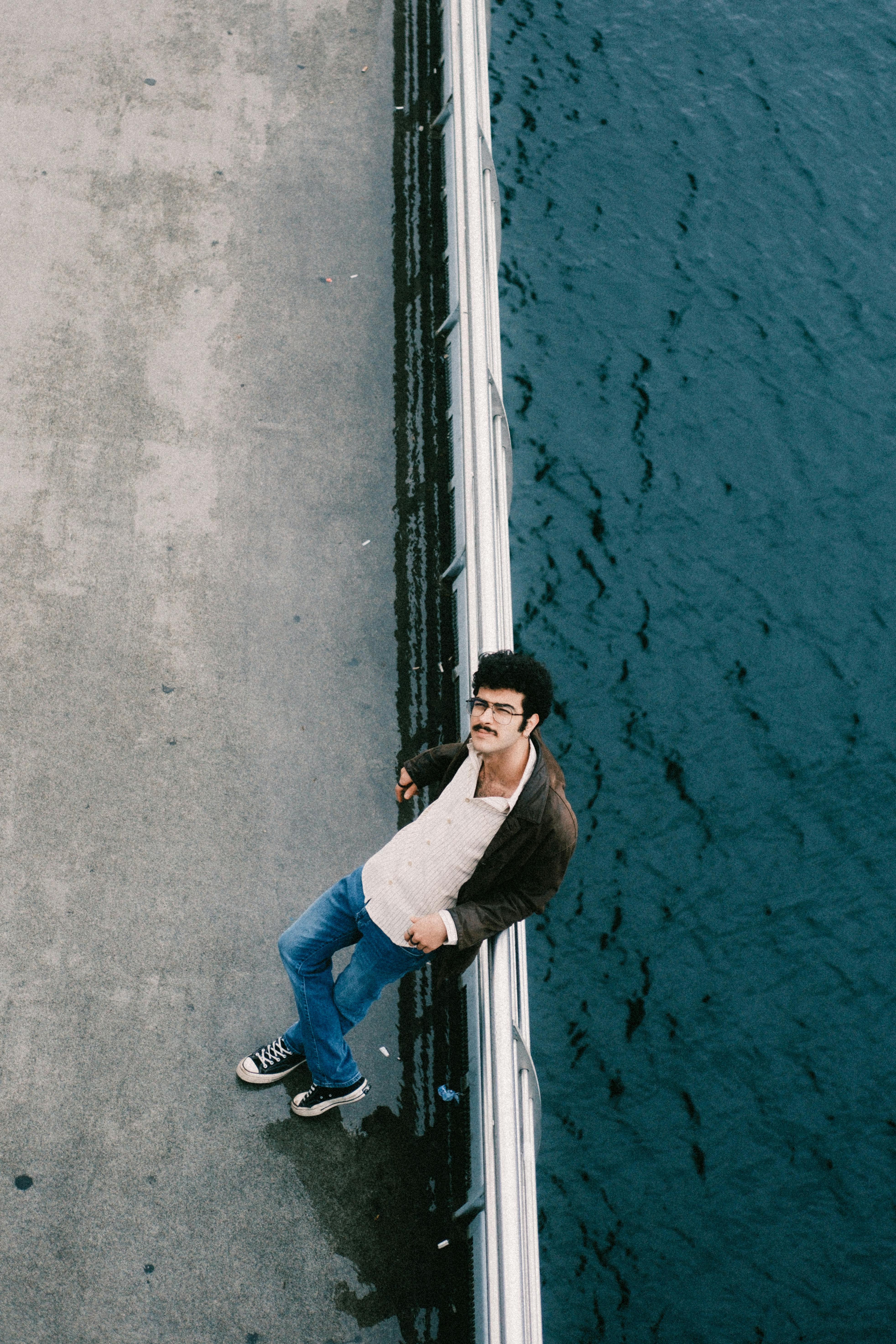 Man Leaning on Rail by Water from Above · Free Stock Photo