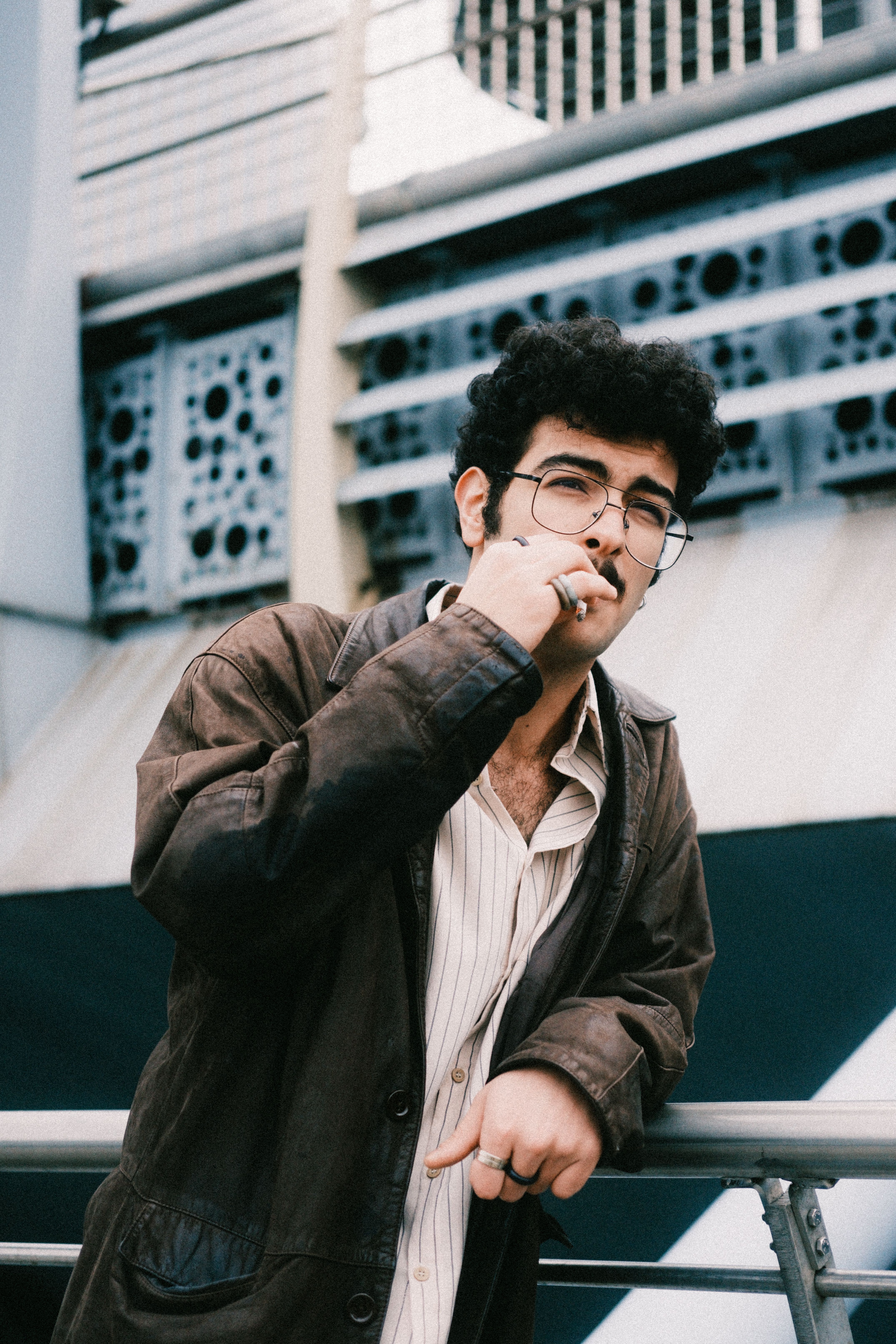 Young Man in Urban Setting Smoking Cigarette · Free Stock Photo
