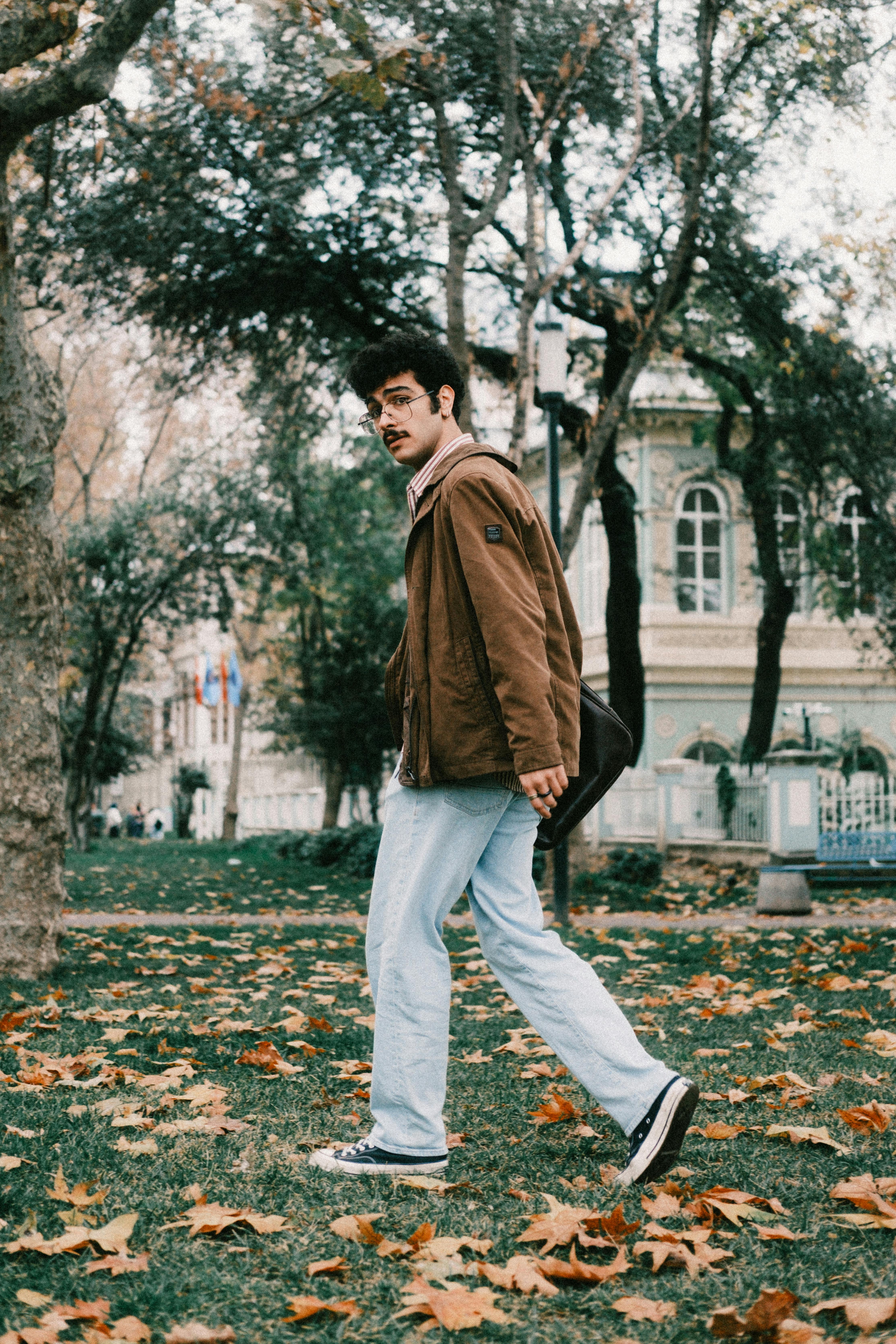 Man Walking in Leaf-Covered Park During Fall · Free Stock Photo