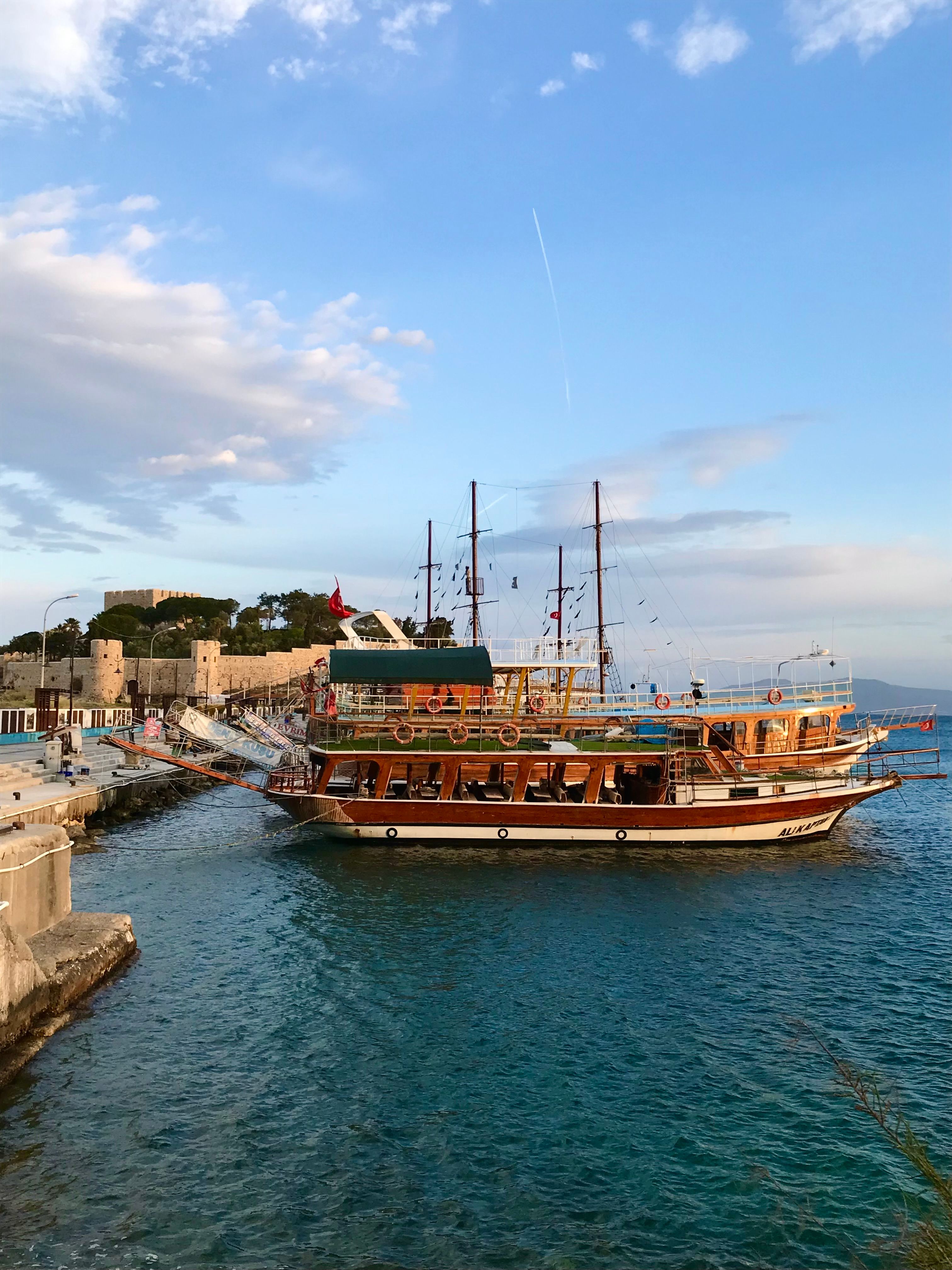 Traditional Wooden Boat Docked by Historic Fortress · Free Stock Photo