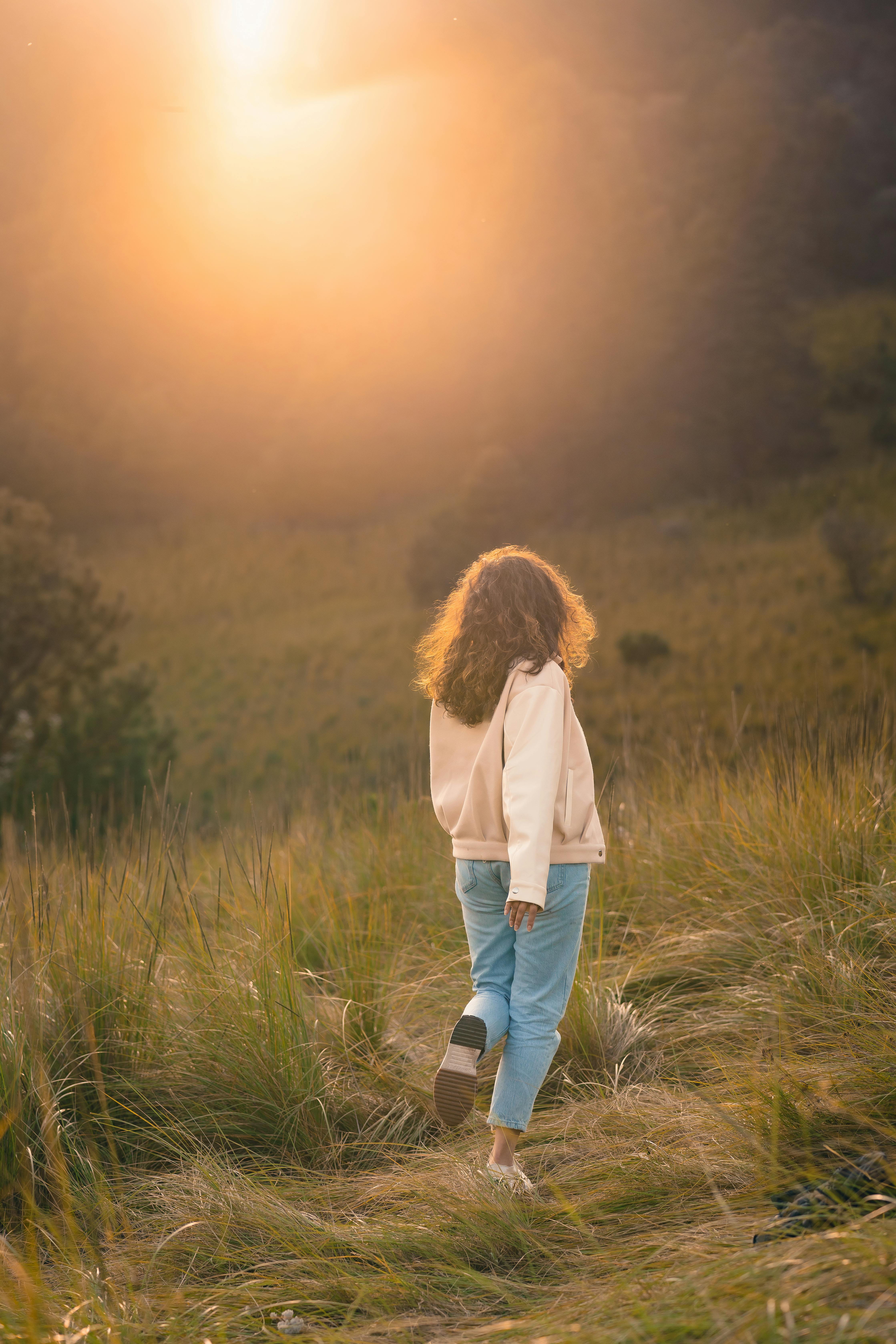 Girl Walking in Sunlit Meadow During Autumn · Free Stock Photo