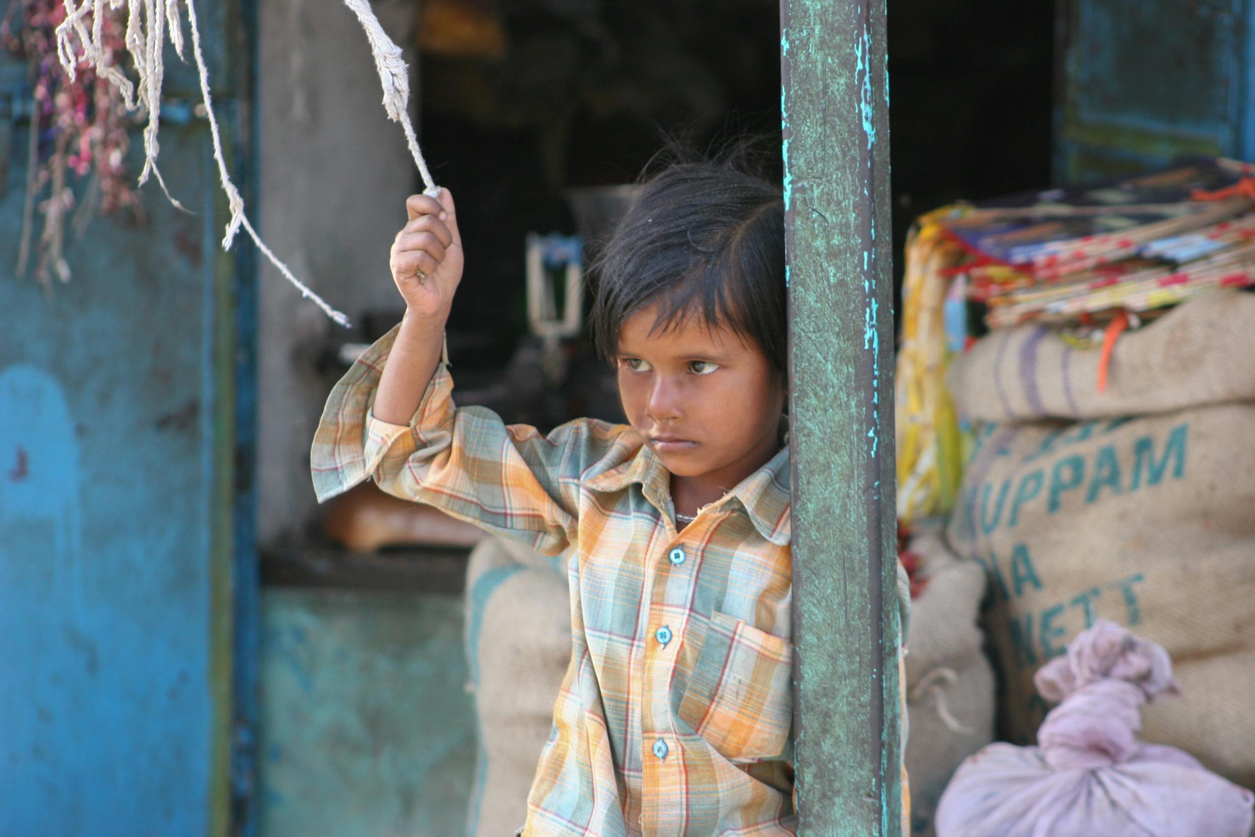 Young Child by Rustic Shop With Colorful Sacks · Free Stock Photo