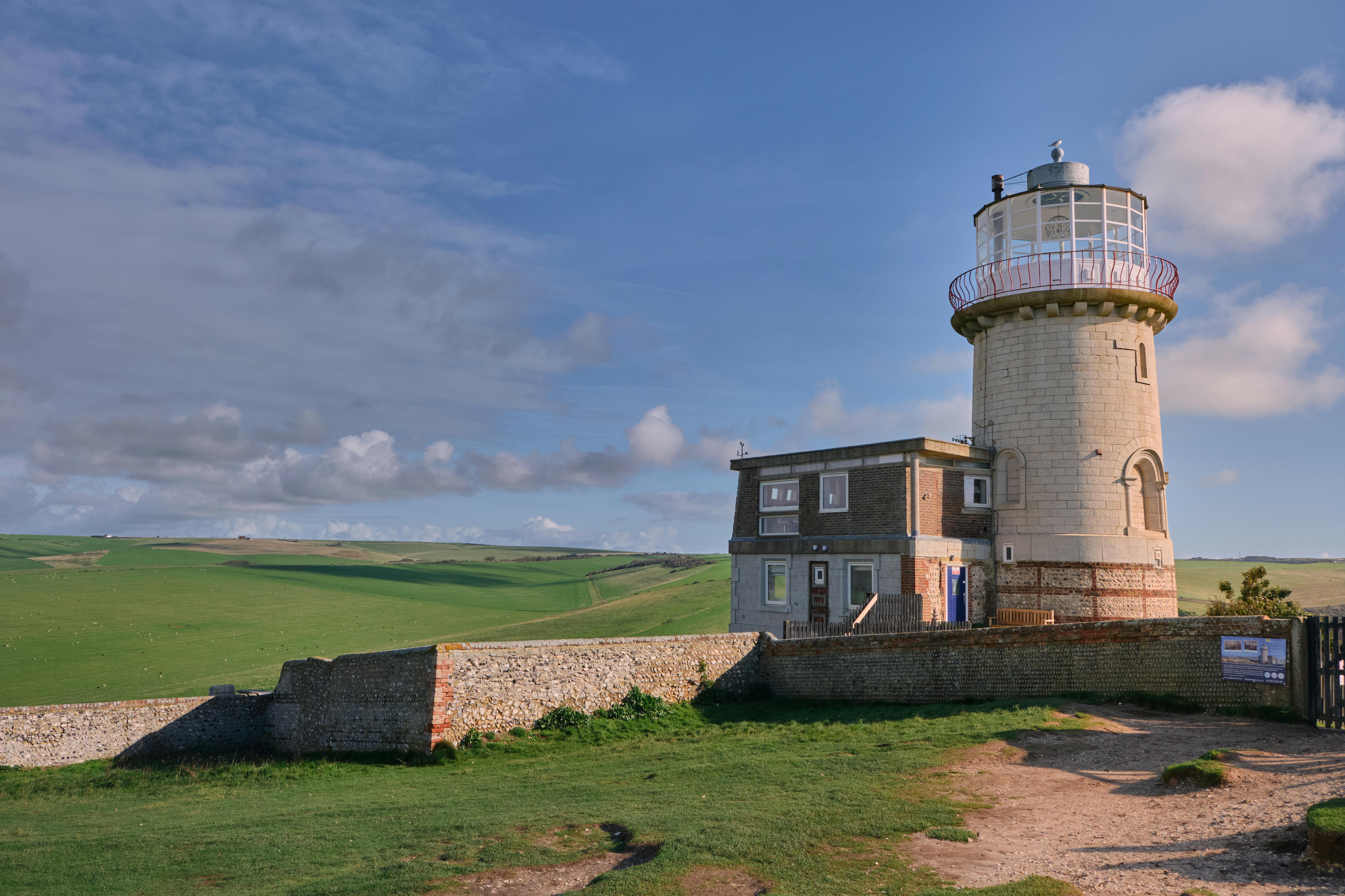 Lighthouse overlooking lush green fields · Free Stock Photo