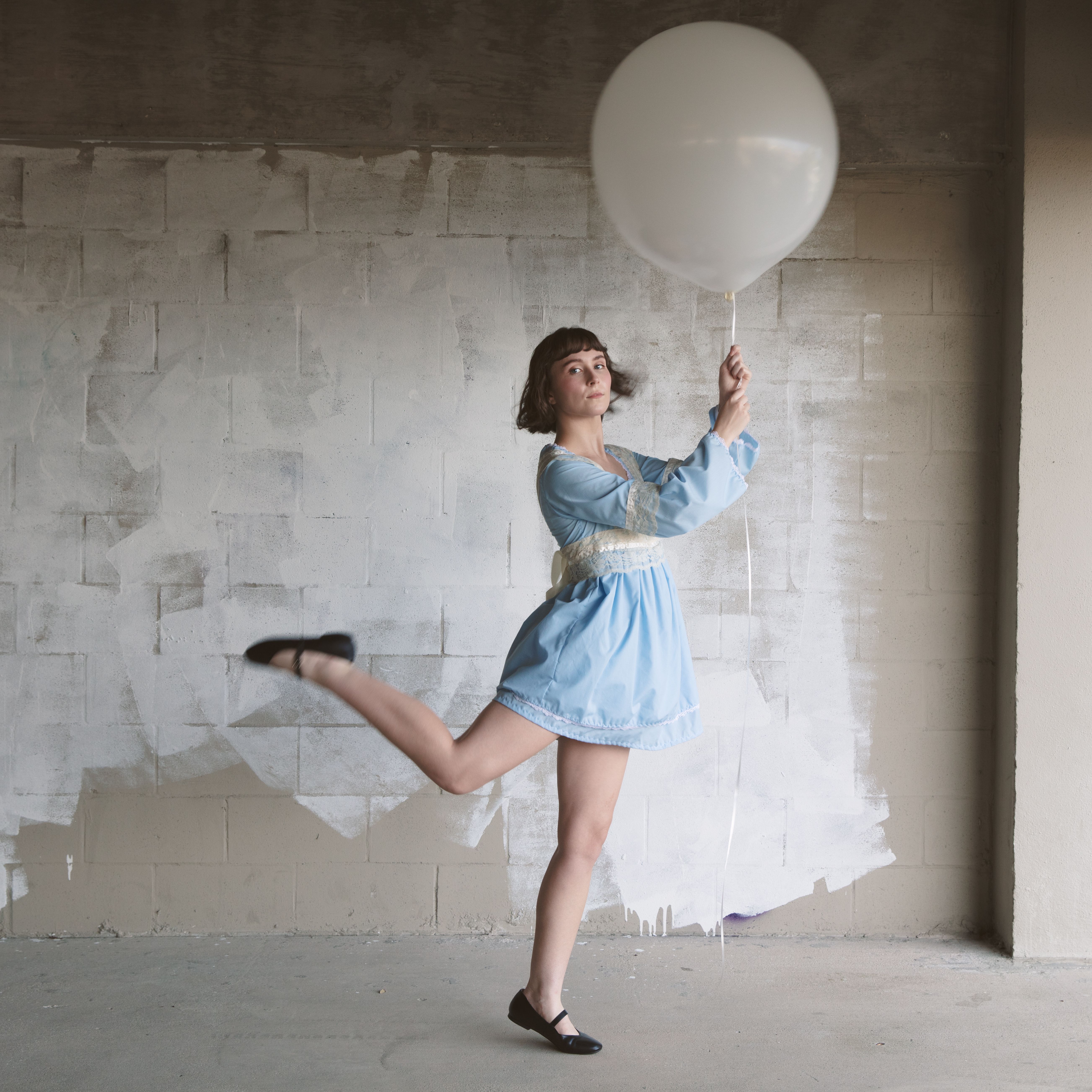Young Woman Dancing with White Balloon Indoors · Free Stock Photo
