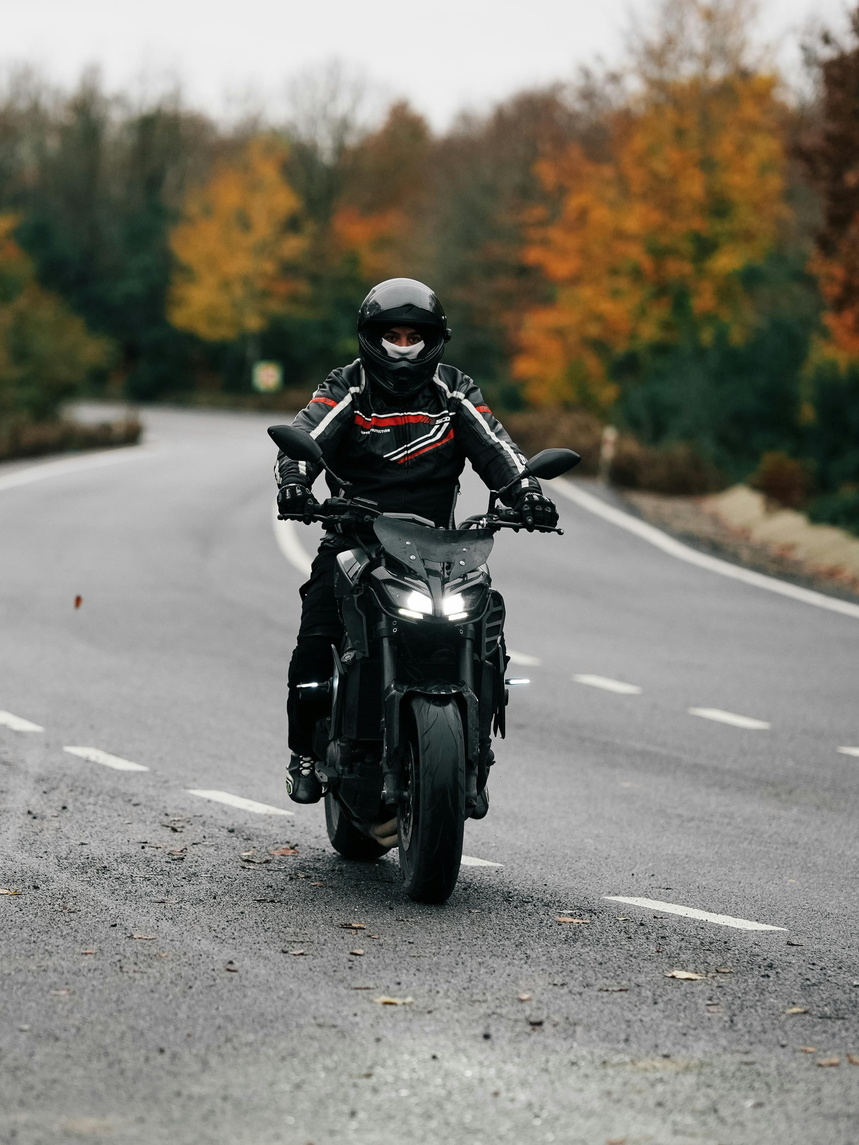 Motorcyclist Riding on Autumn Country Road · Free Stock Photo