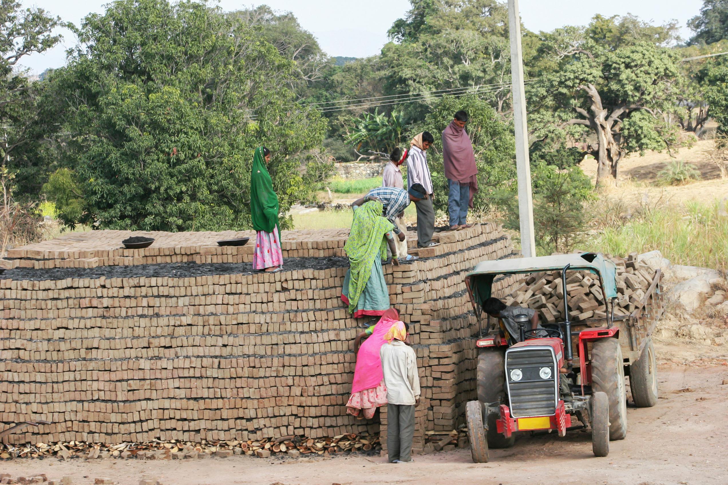 Workers Loading Bricks onto Tractor in Rural Setting · Free Stock Photo