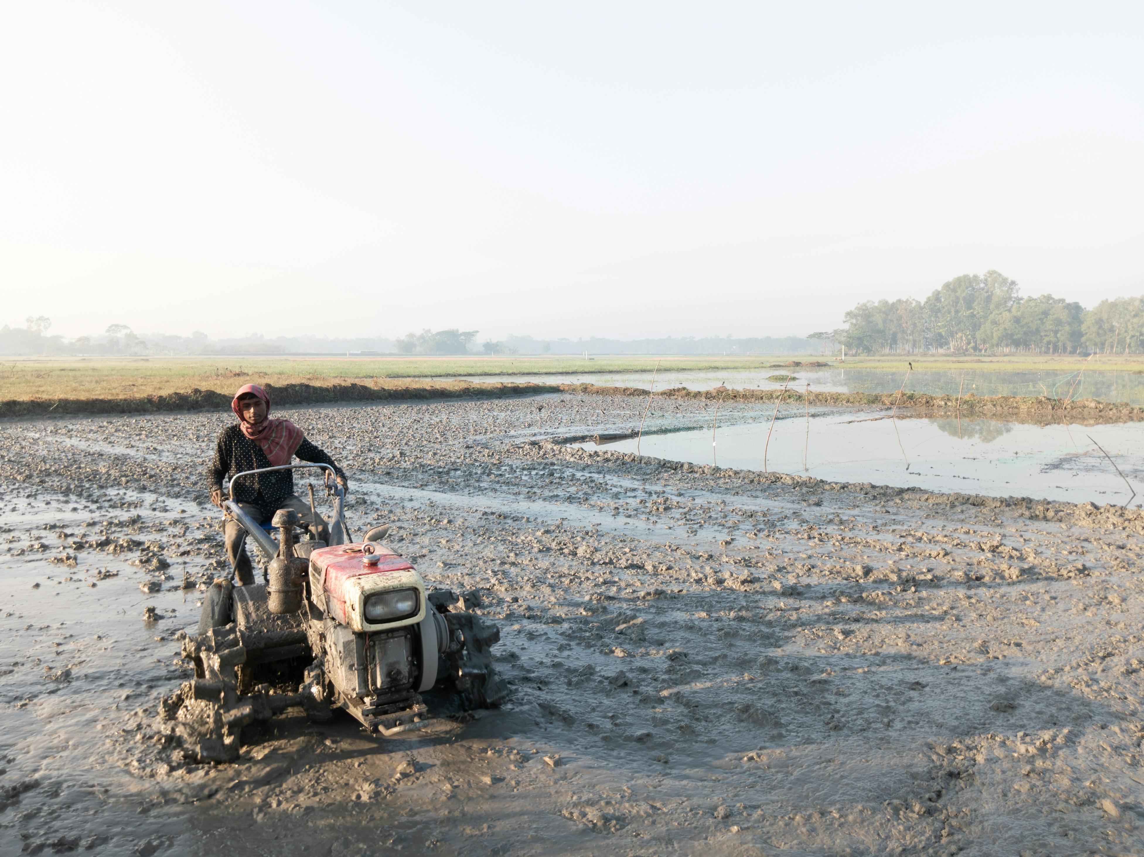 Farmer Operating Tractor in Muddy Field · Free Stock Photo