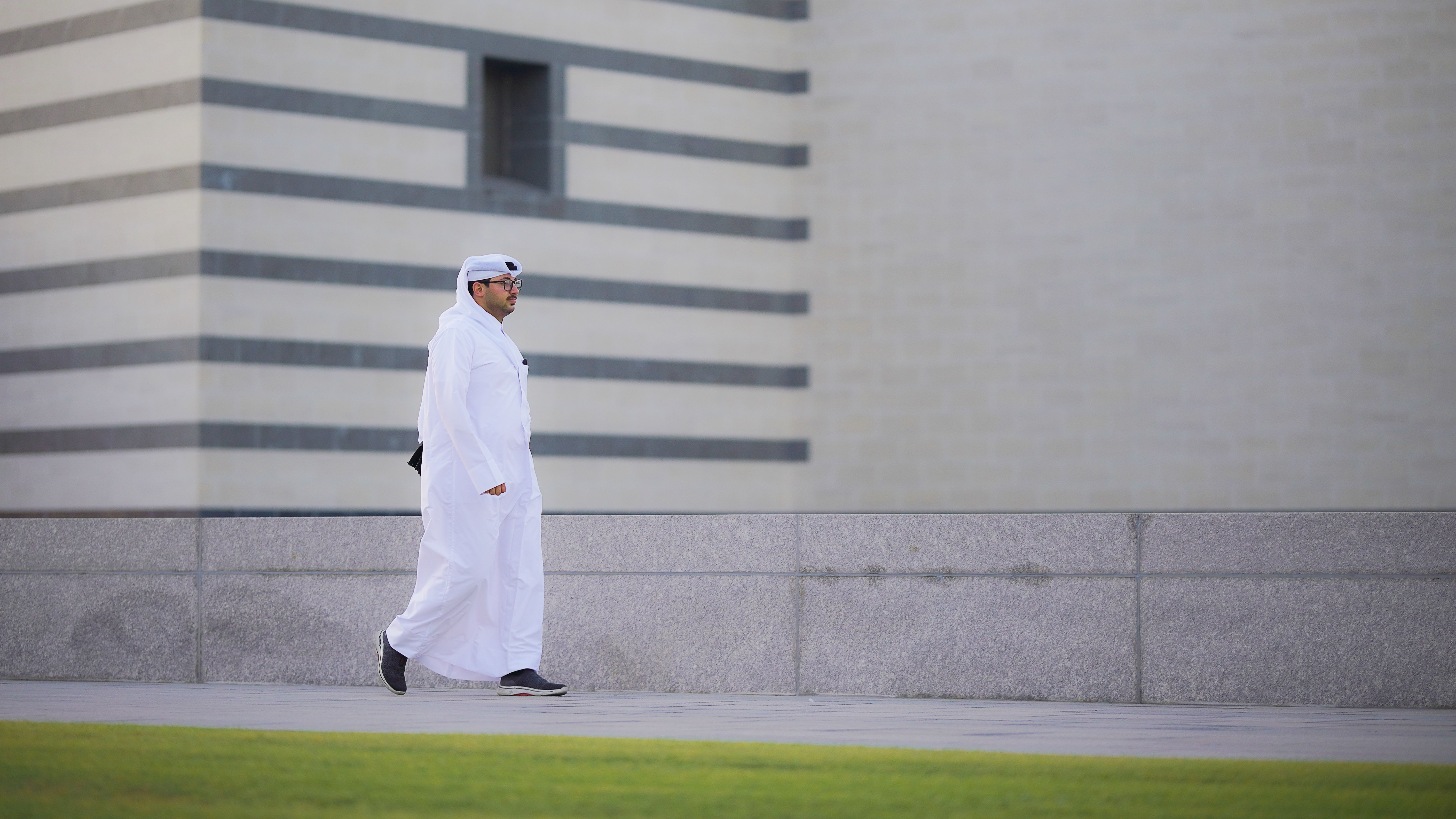 Un Homme Marchant Près D'une Architecture Moderne à Doha · Photo gratuite