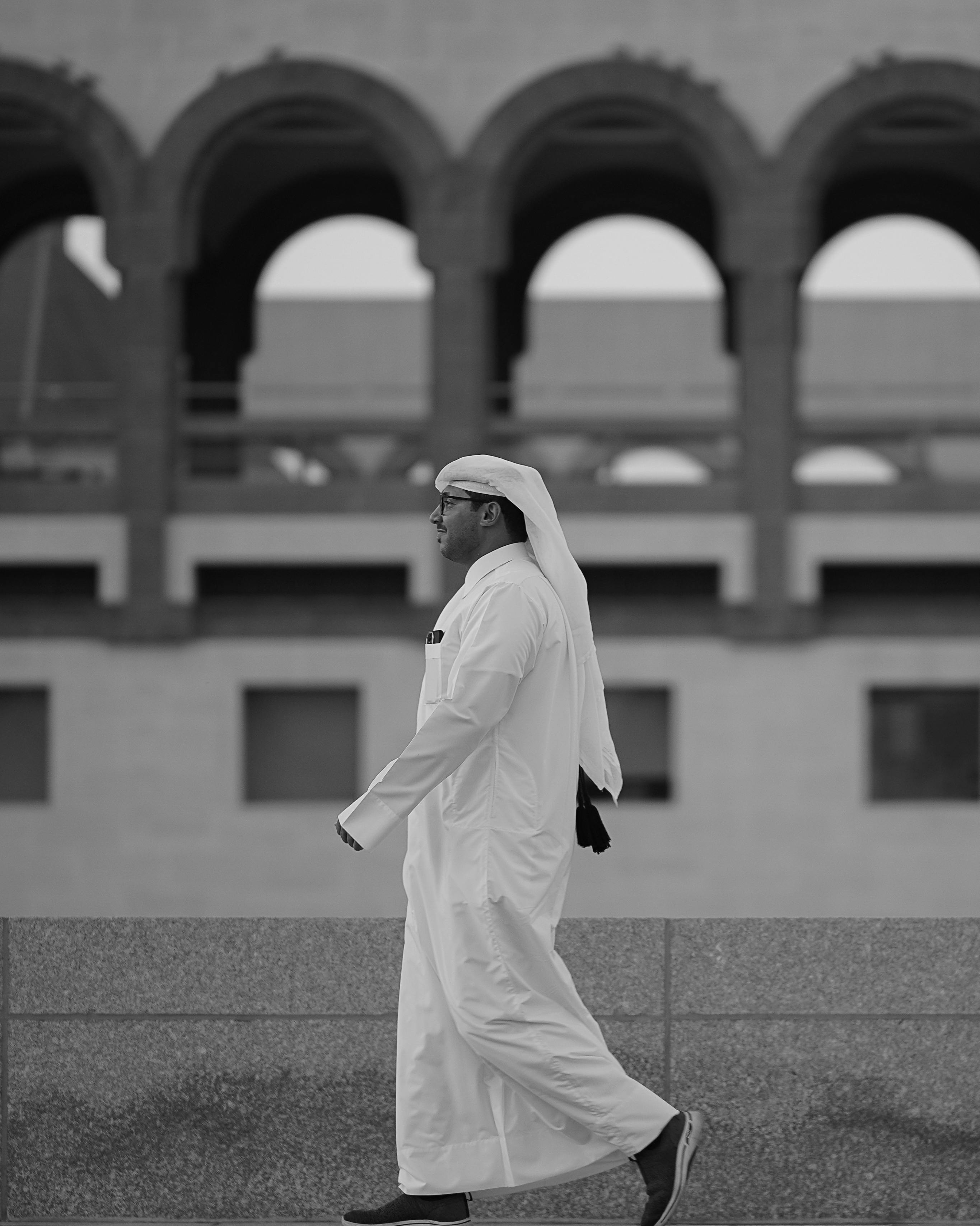Traditional Qatari Man Walking by Doha Architecture · Free Stock Photo