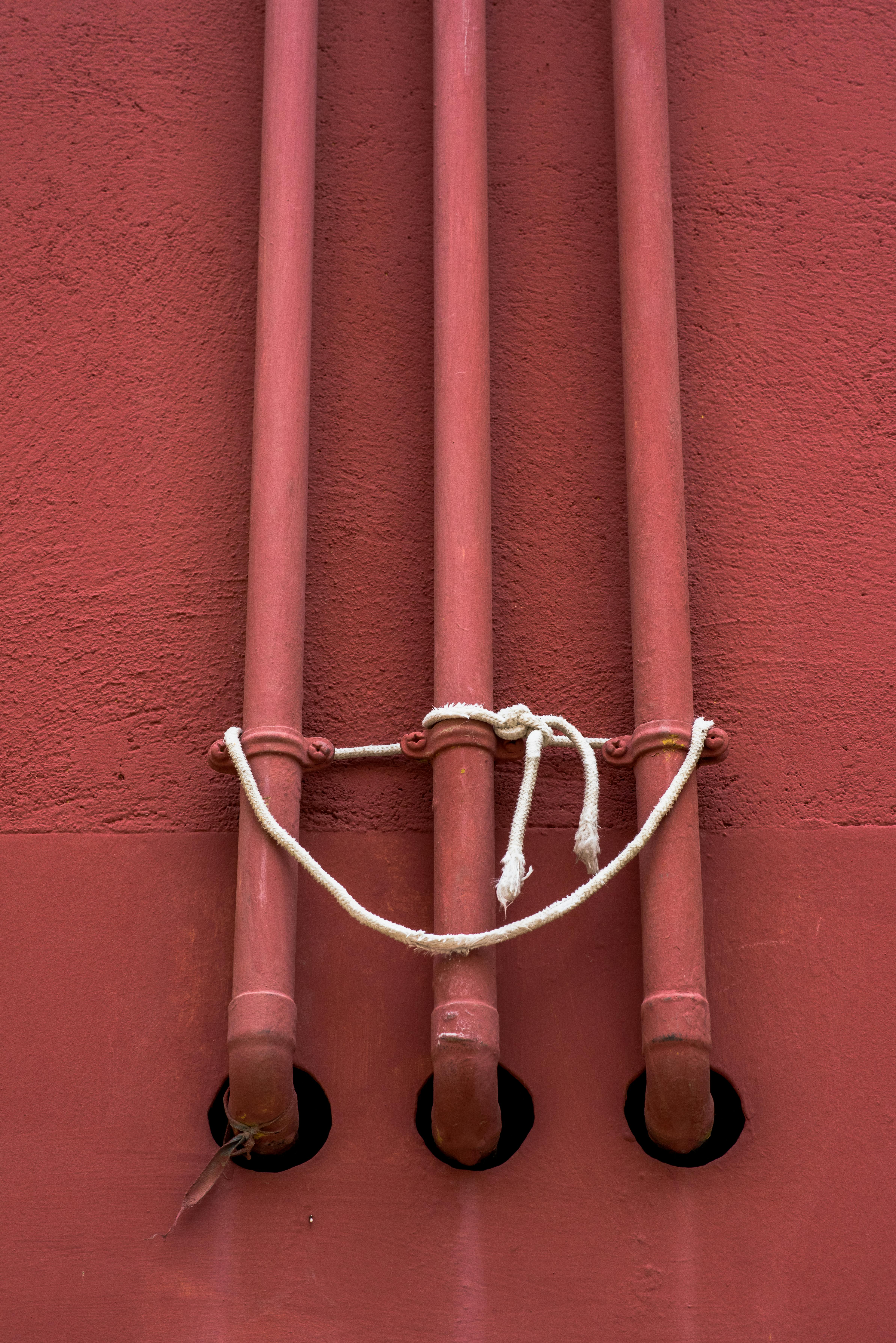 Abstract Red Wall with Pipes and Rope Detail · Free Stock Photo