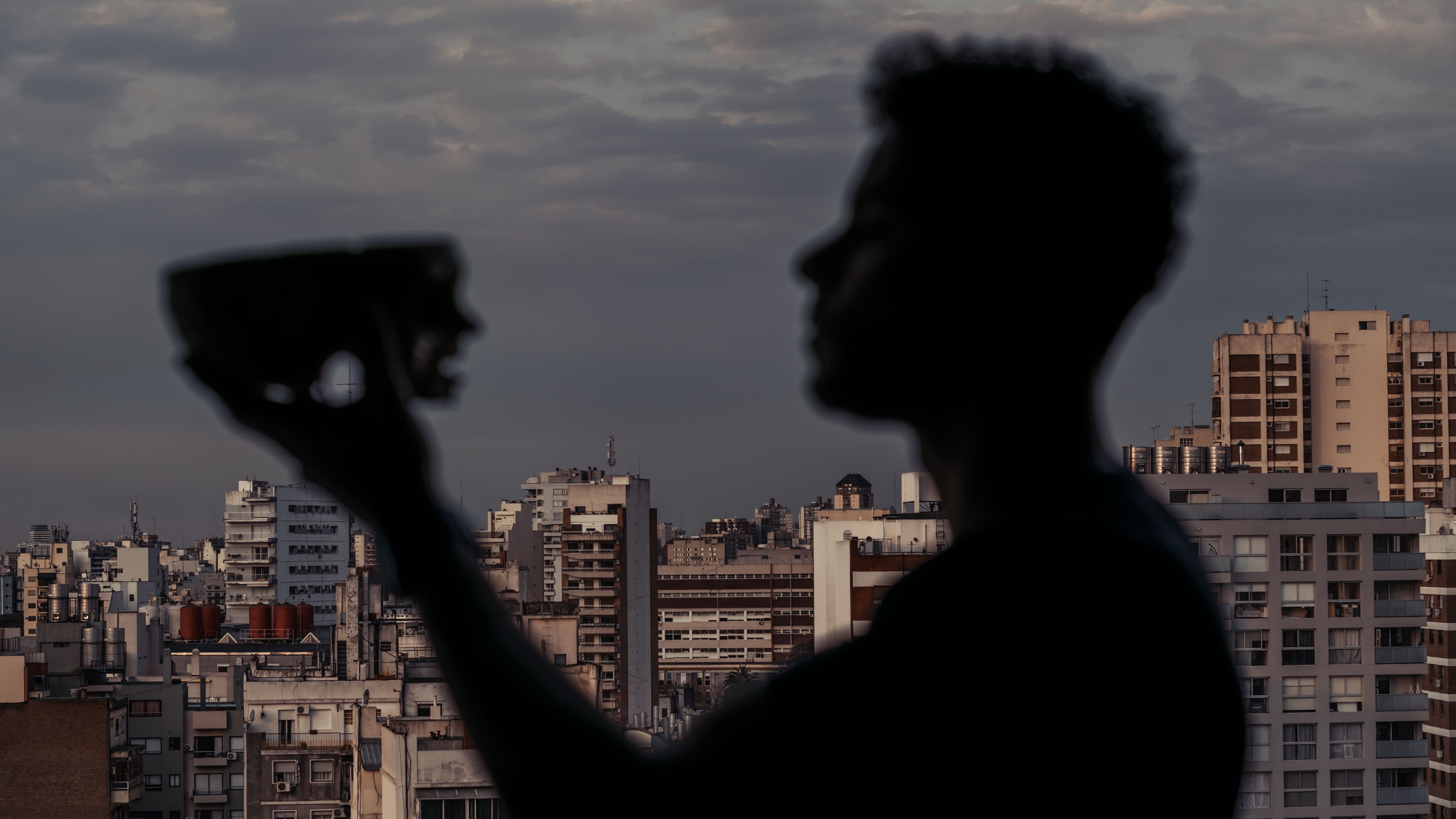 Silhouette of Person Holding Skull in Urban Setting · Free Stock Photo