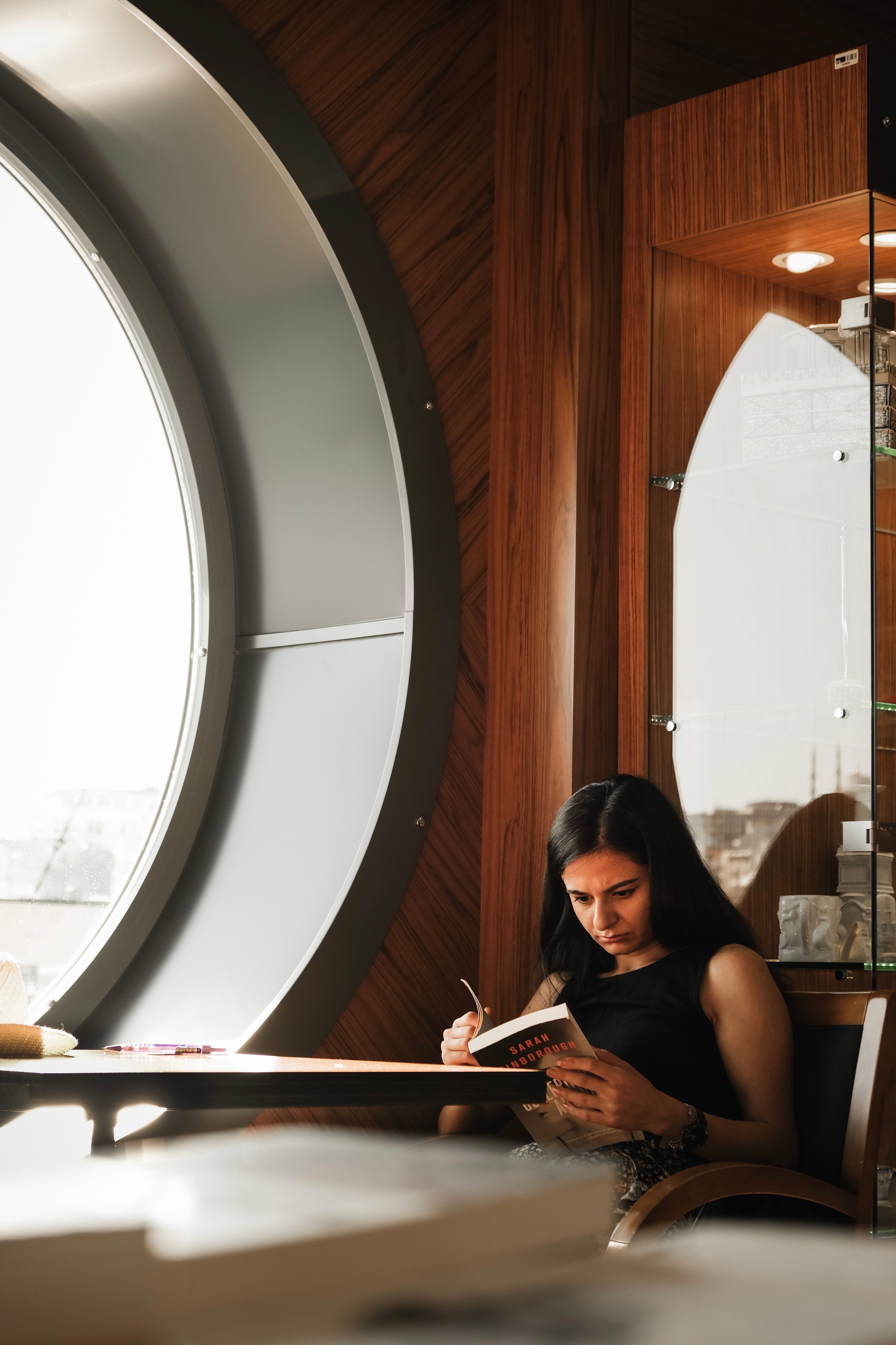 Contemplative Woman Reading by Circular Window · Free Stock Photo