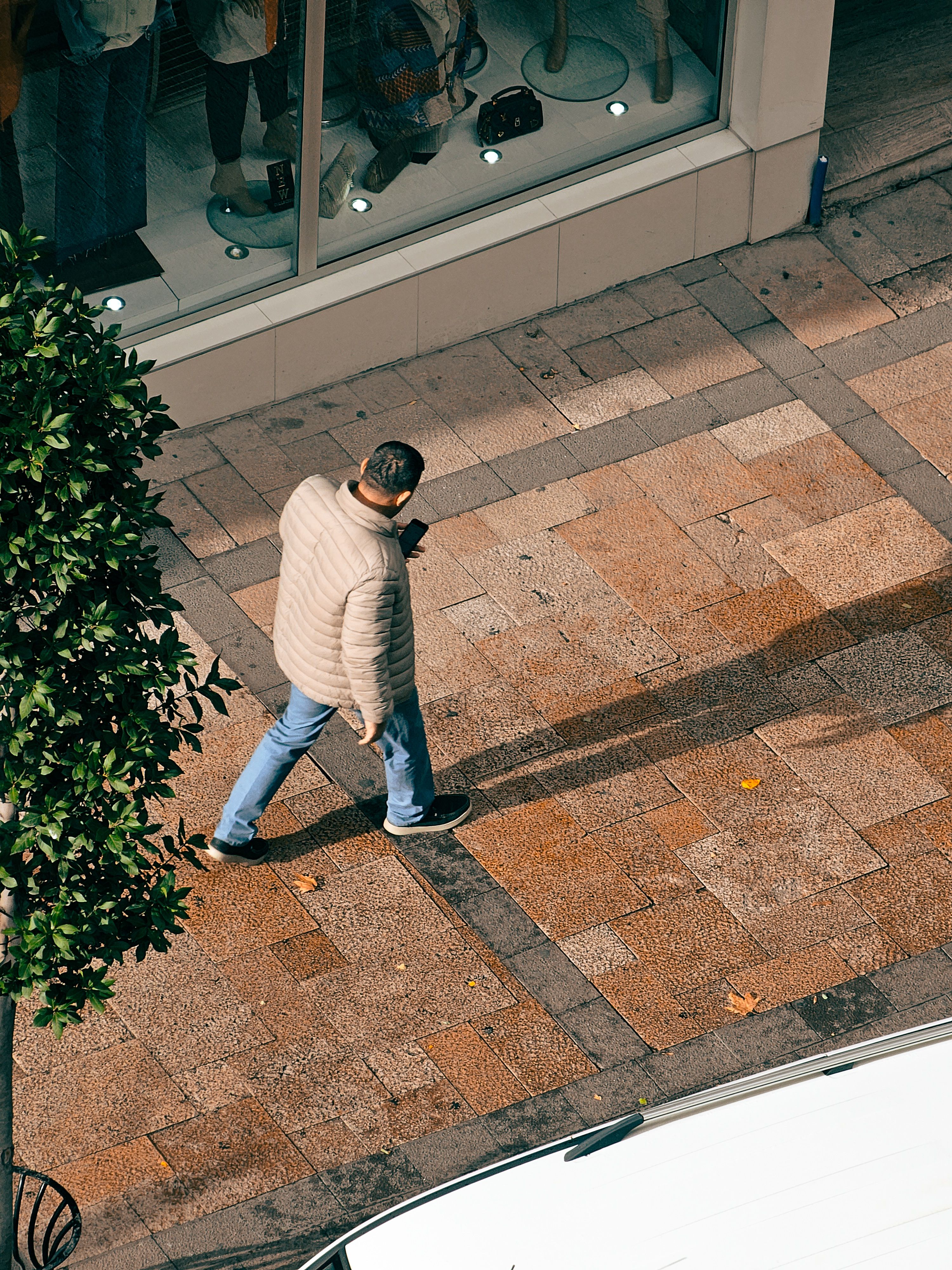Man Walking on Urban Pavement Under Bright Sunlight · Free Stock Photo