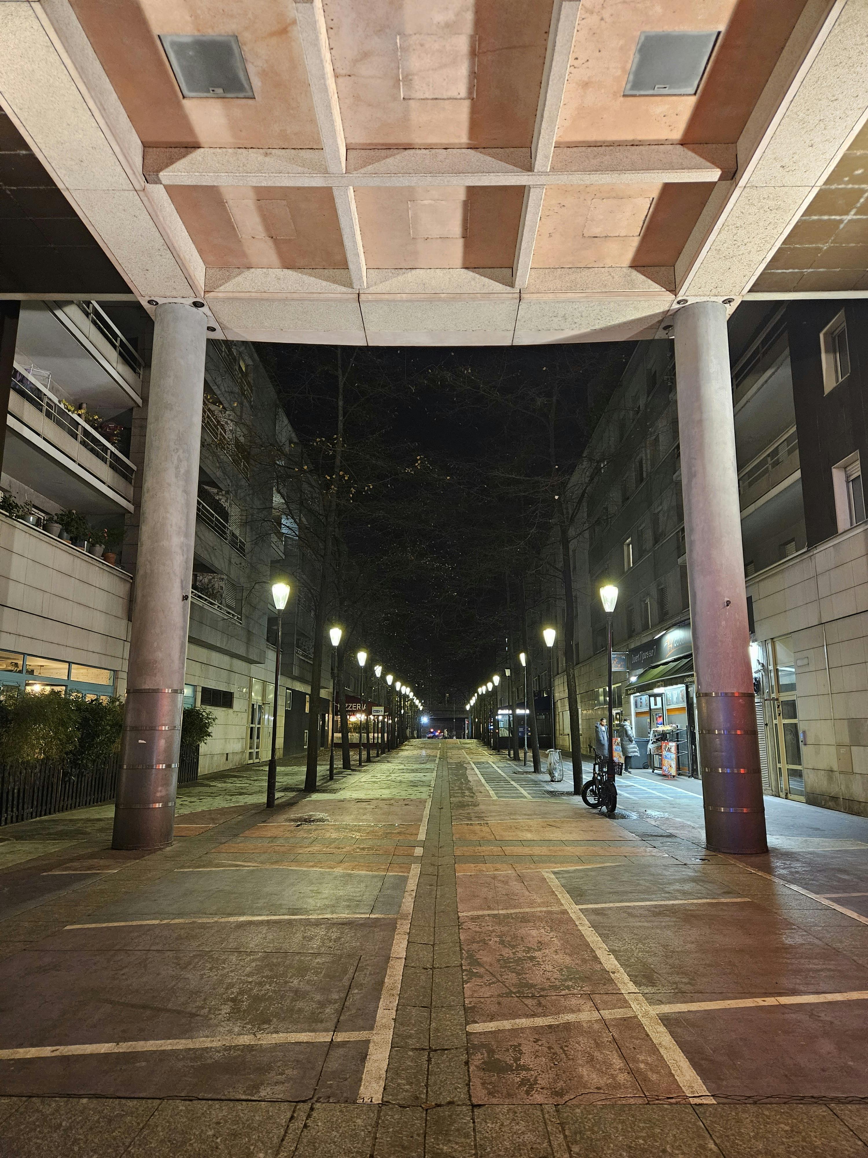Nighttime Urban Street Under Architectural Archway · Free Stock Photo