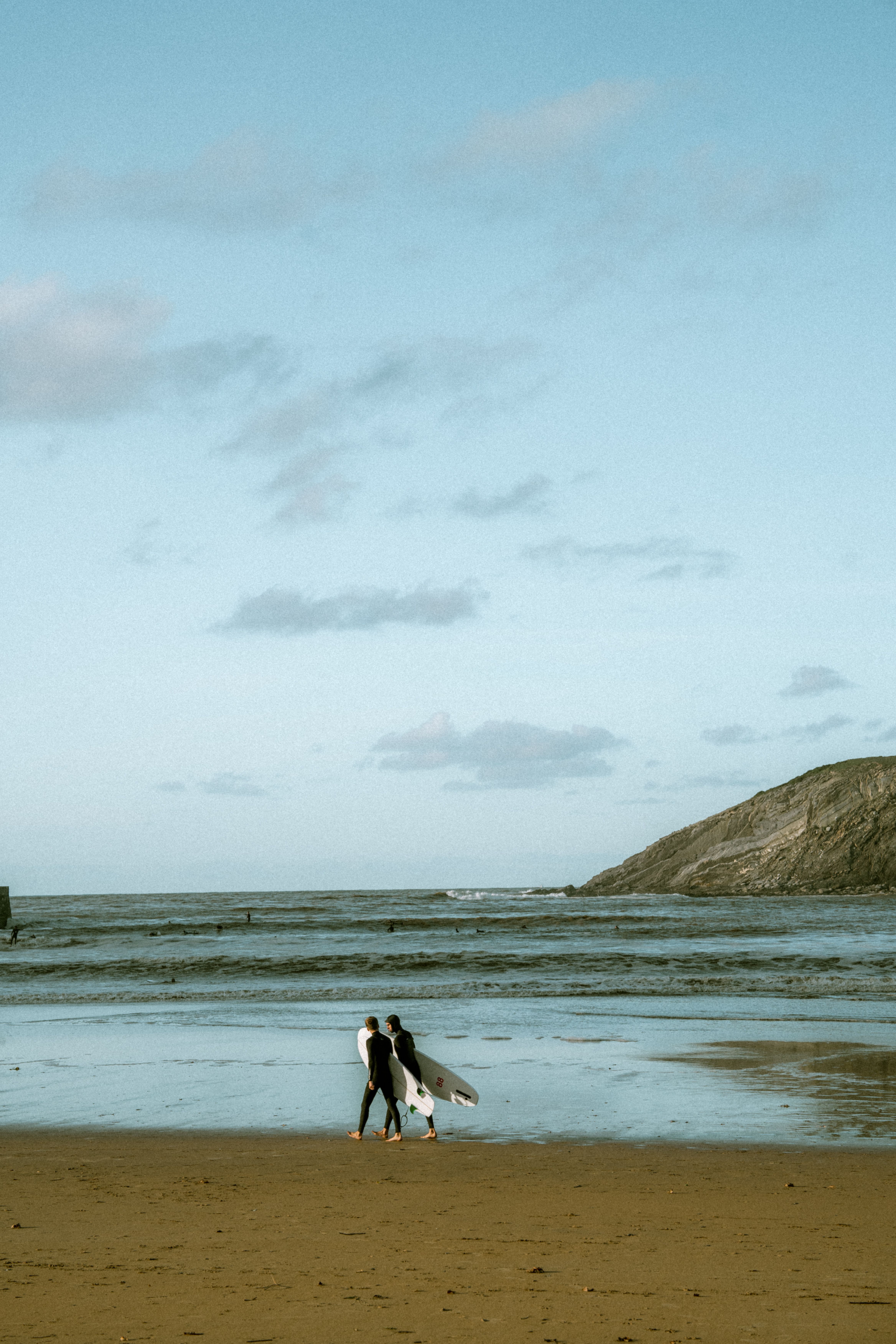 Couple Surfing on a Scenic Beach at Sunset · Free Stock Photo