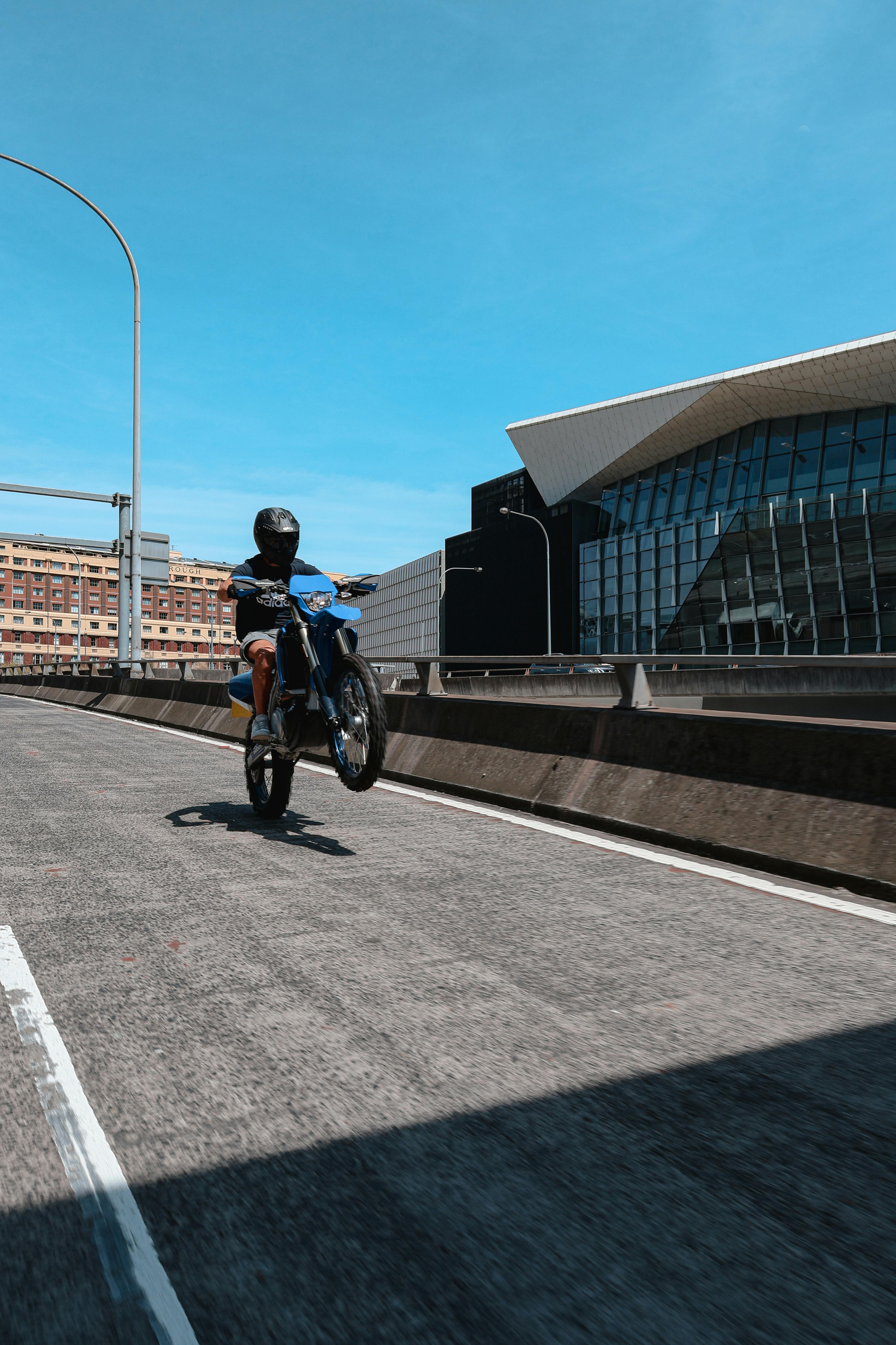 Motorcyclist Performing a Wheelie on an Urban Highway · Free Stock Photo