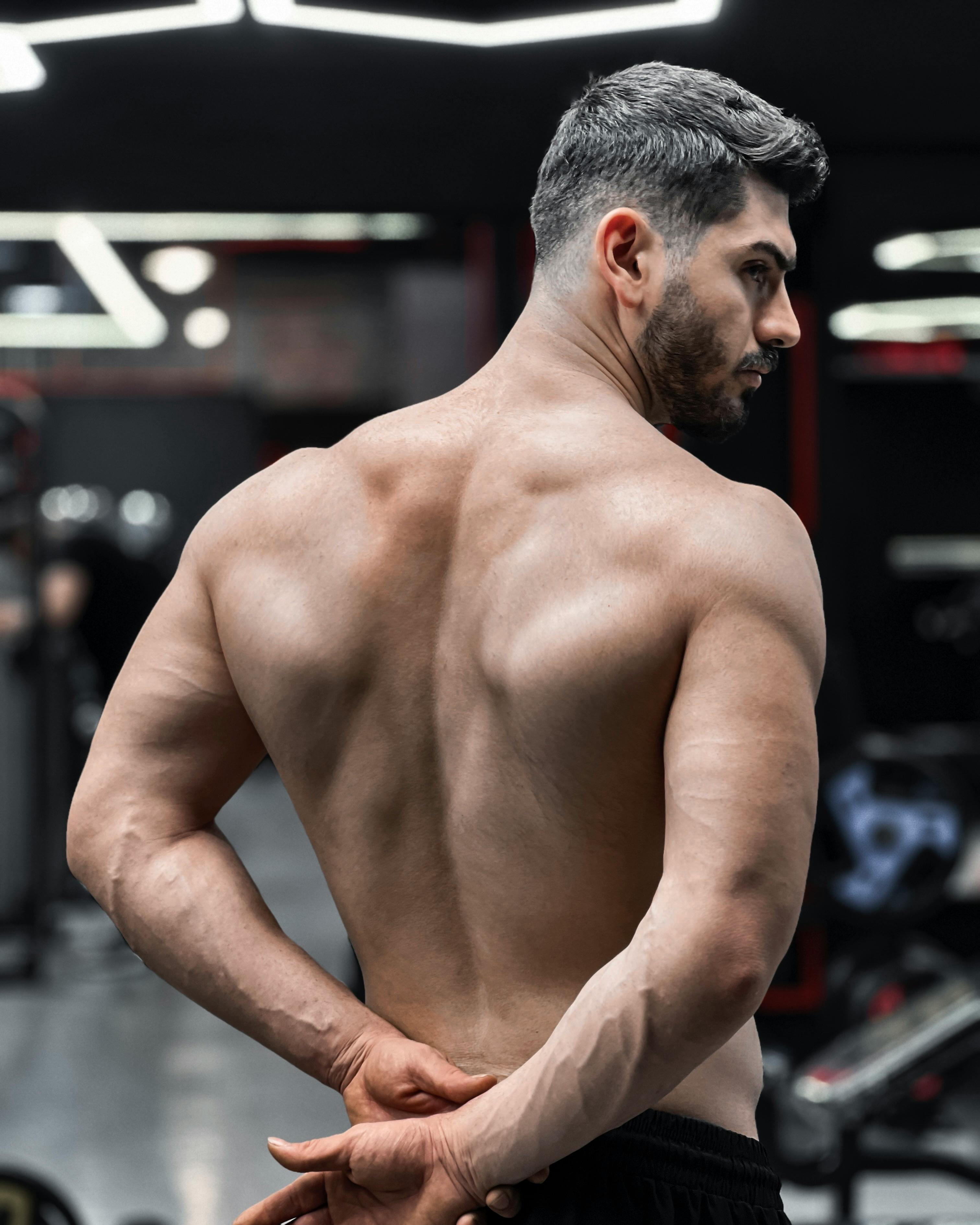 Muscular Man in Gym Demonstrating Back Muscles · Free Stock Photo