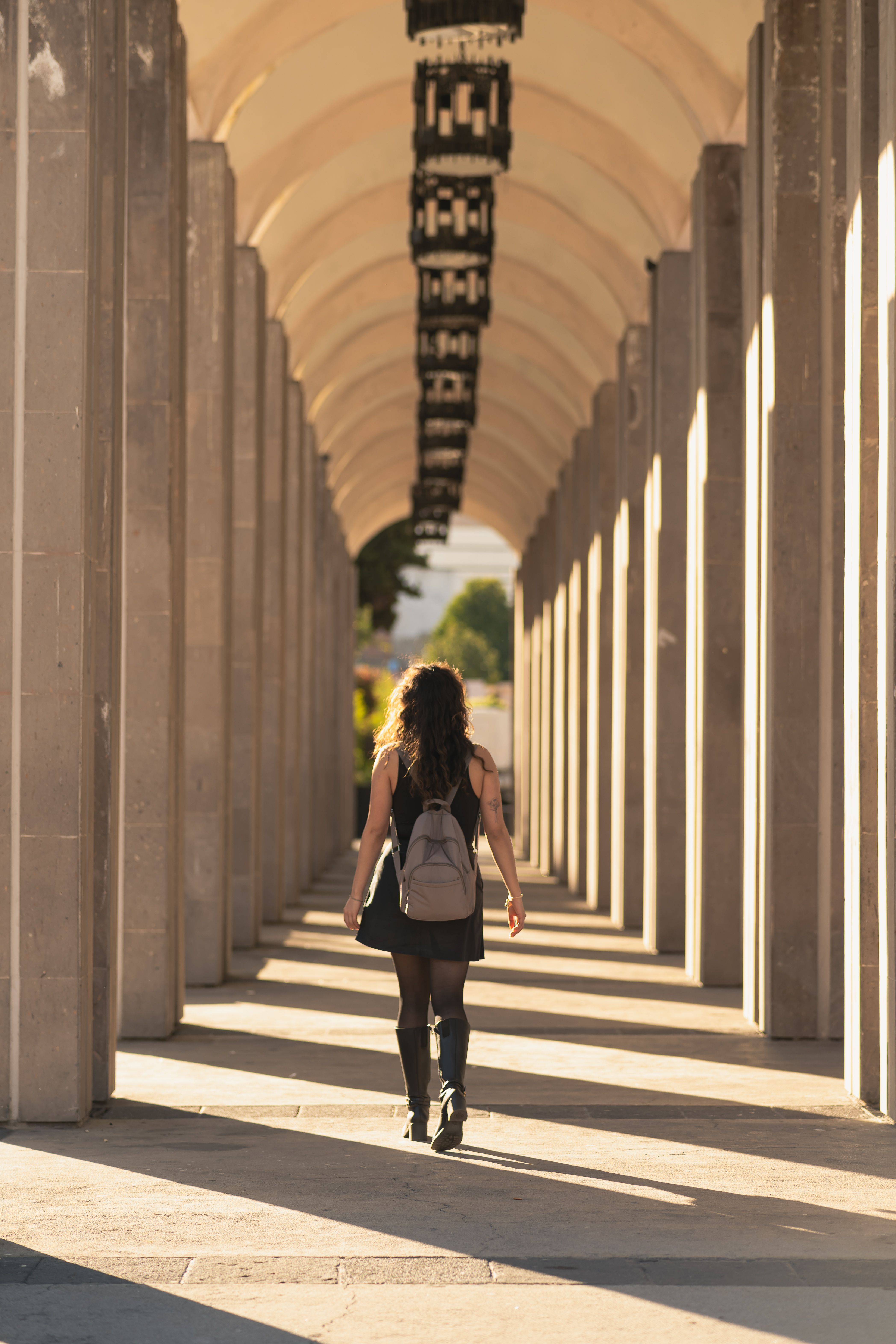 Back View of Woman Walking Through Architectural Arches · Free Stock Photo